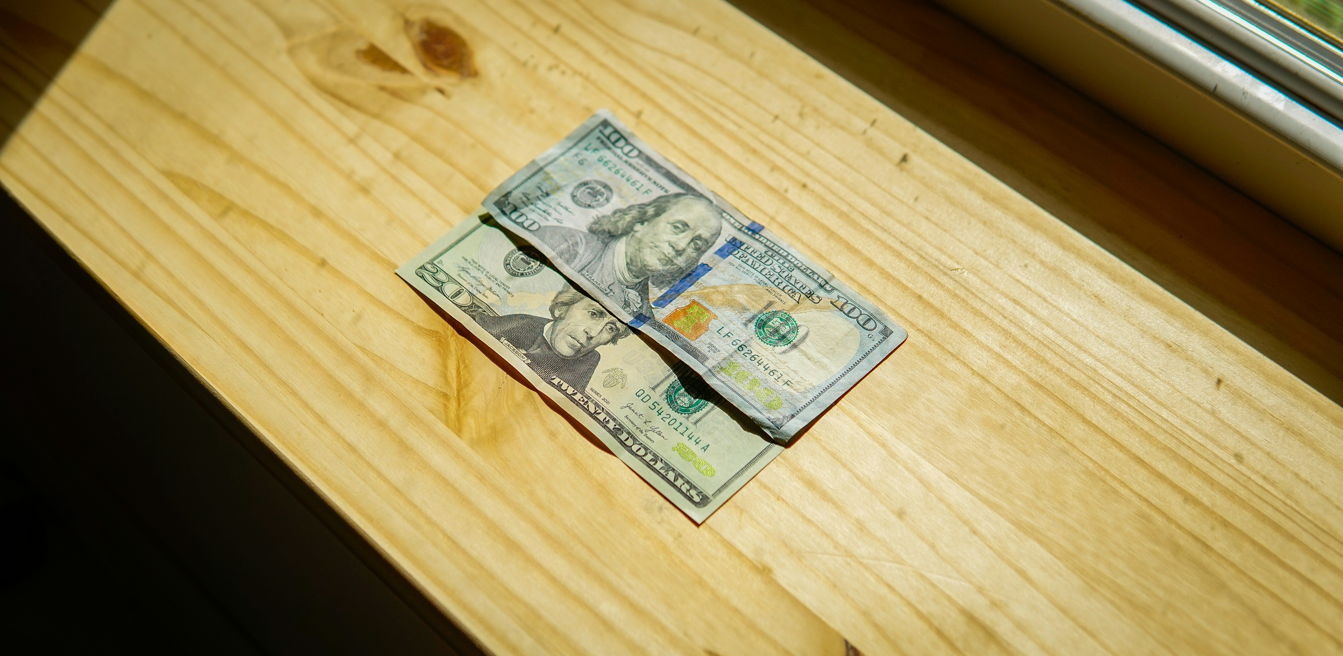 Folded cash on a sunlit wooden sill