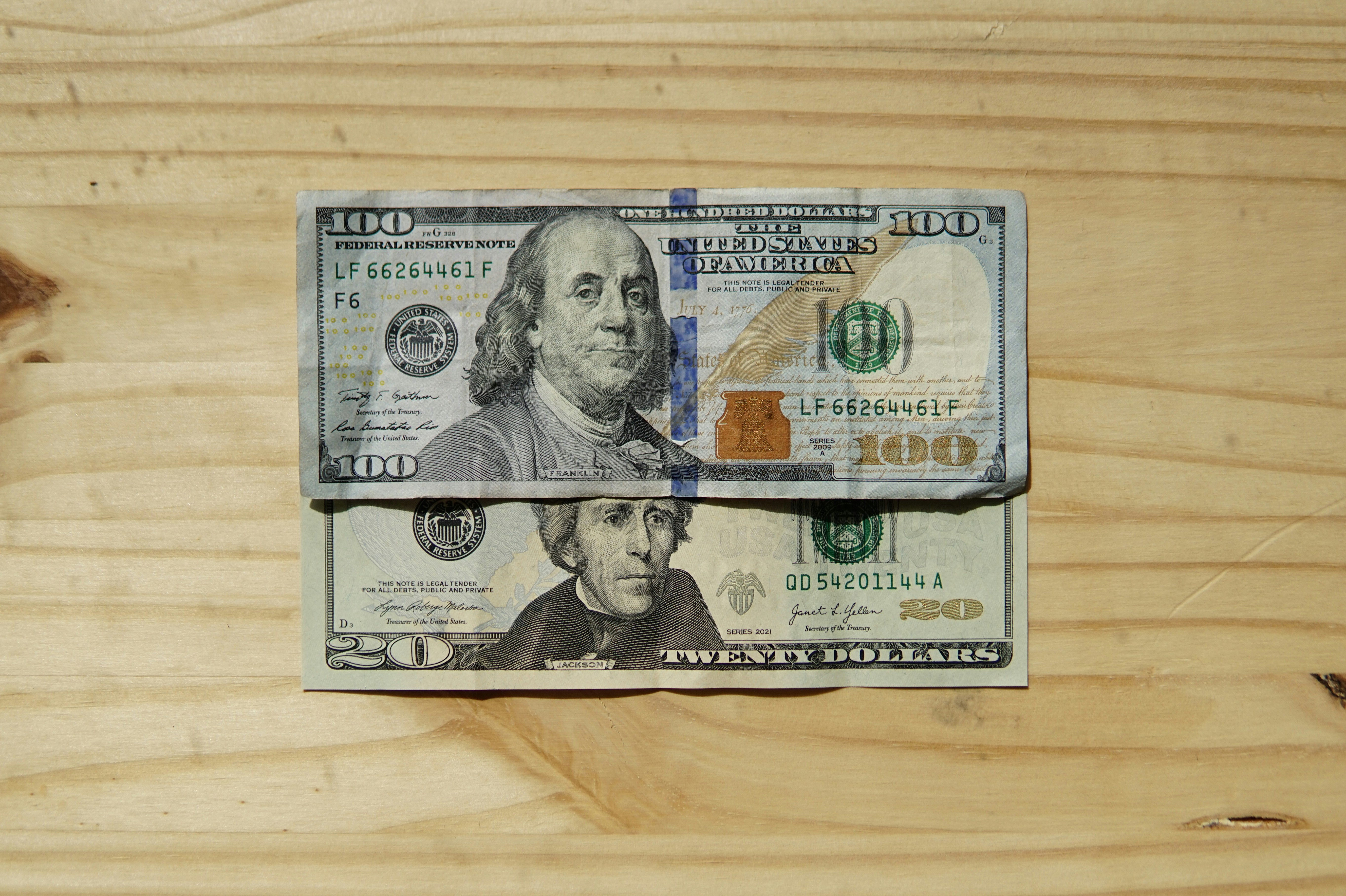 Folded fortunes: a duo of hundred-dollar bills resting on raw timber