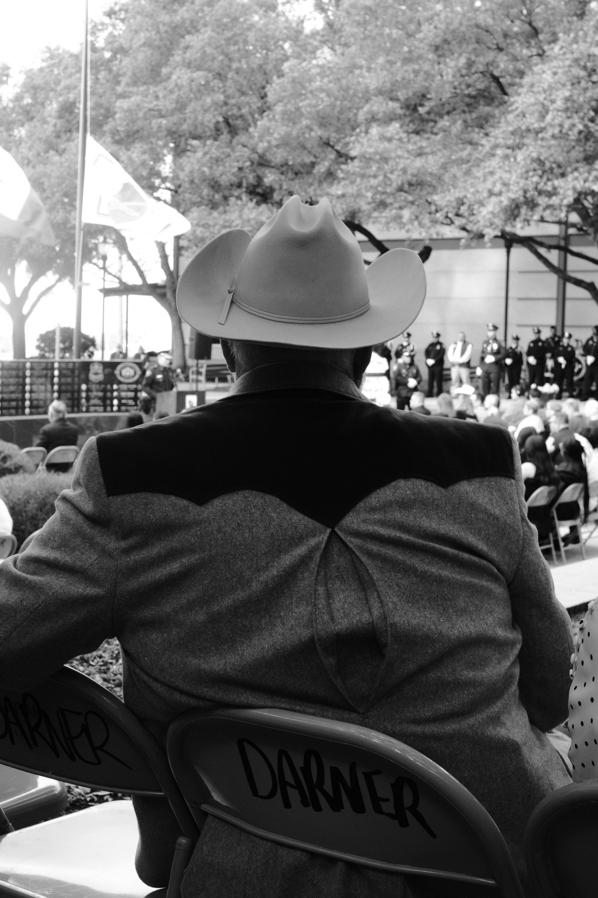Curved Back, Lone Cowboy: A Moment Behind the Crowd
