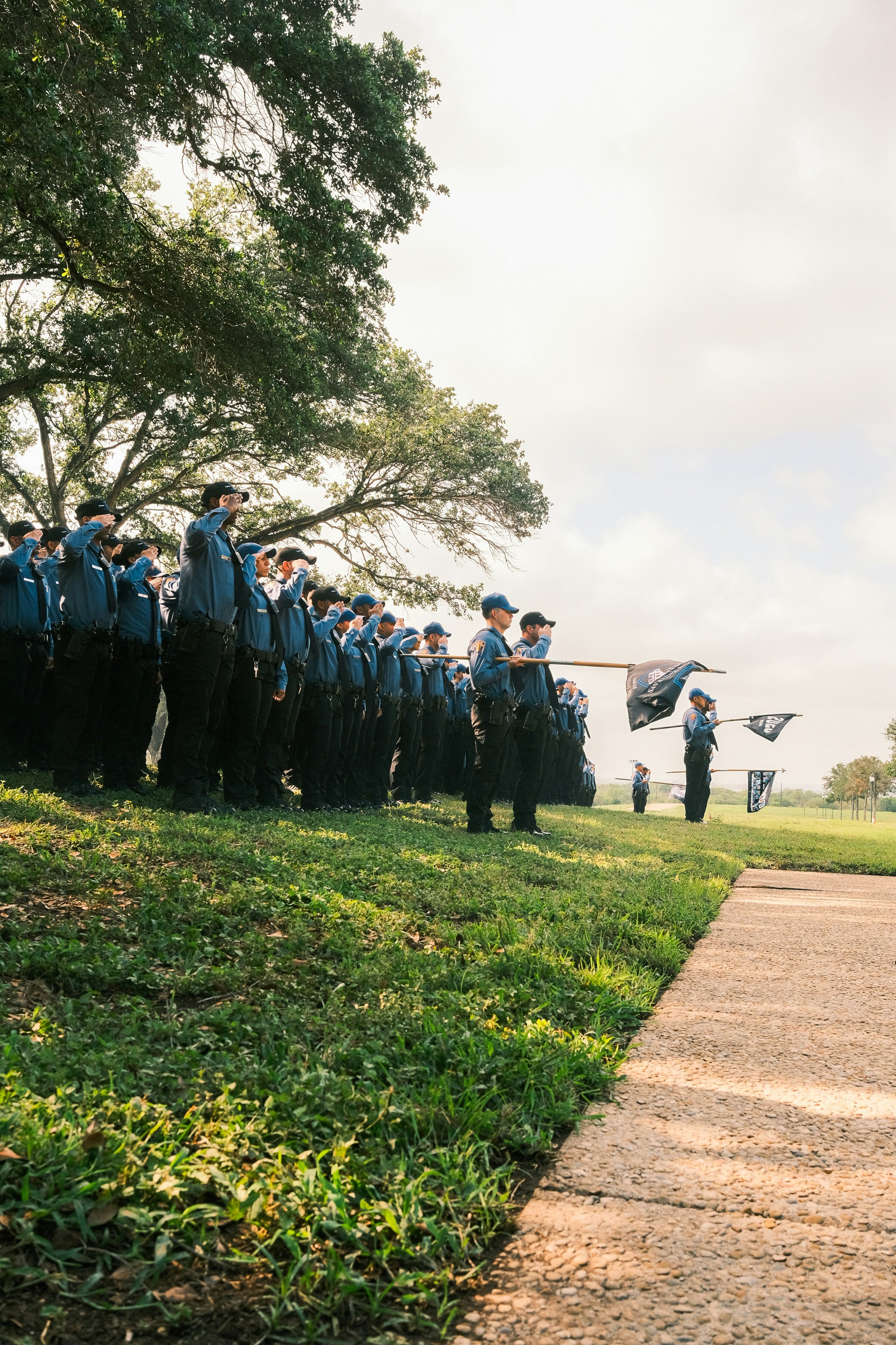 Marching Unity: A Formation of Blue Uniformed Cadets Under a Shaded canopy