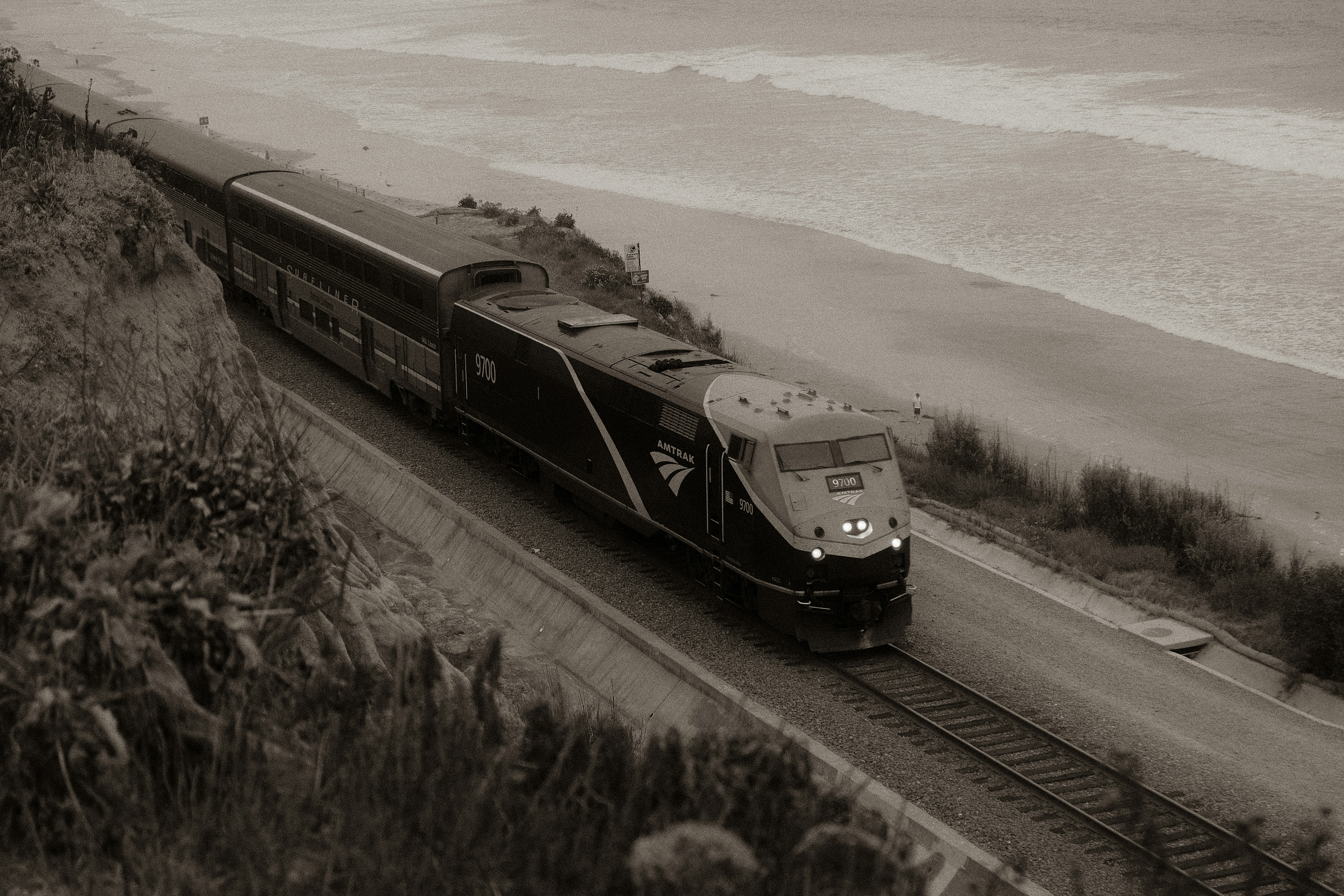 Coastal Rail in Sepia: a lone diesel glides along the cliffside track