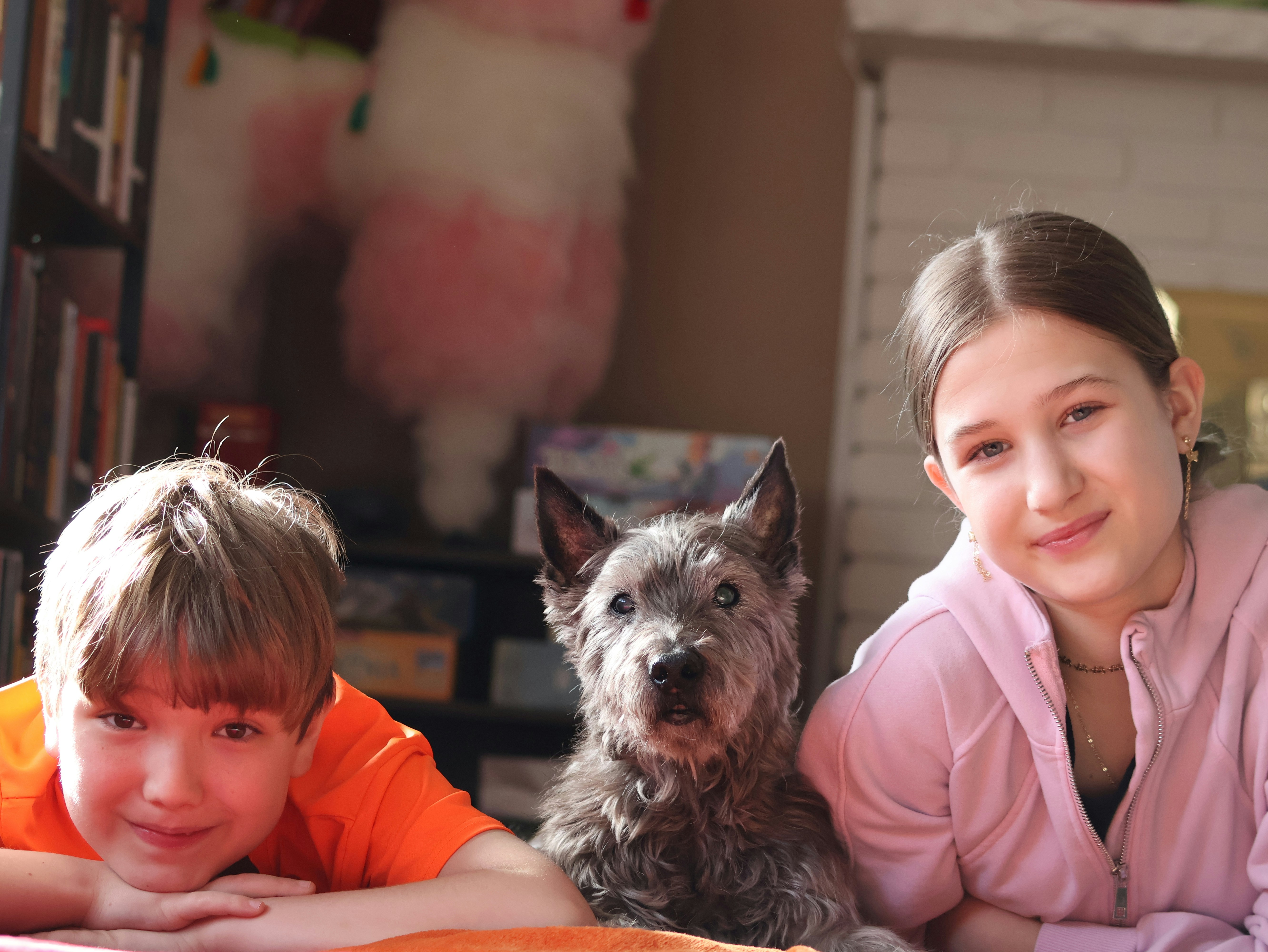 Cairn Terrier, Boy & Girl pose together indoors with board games in the background