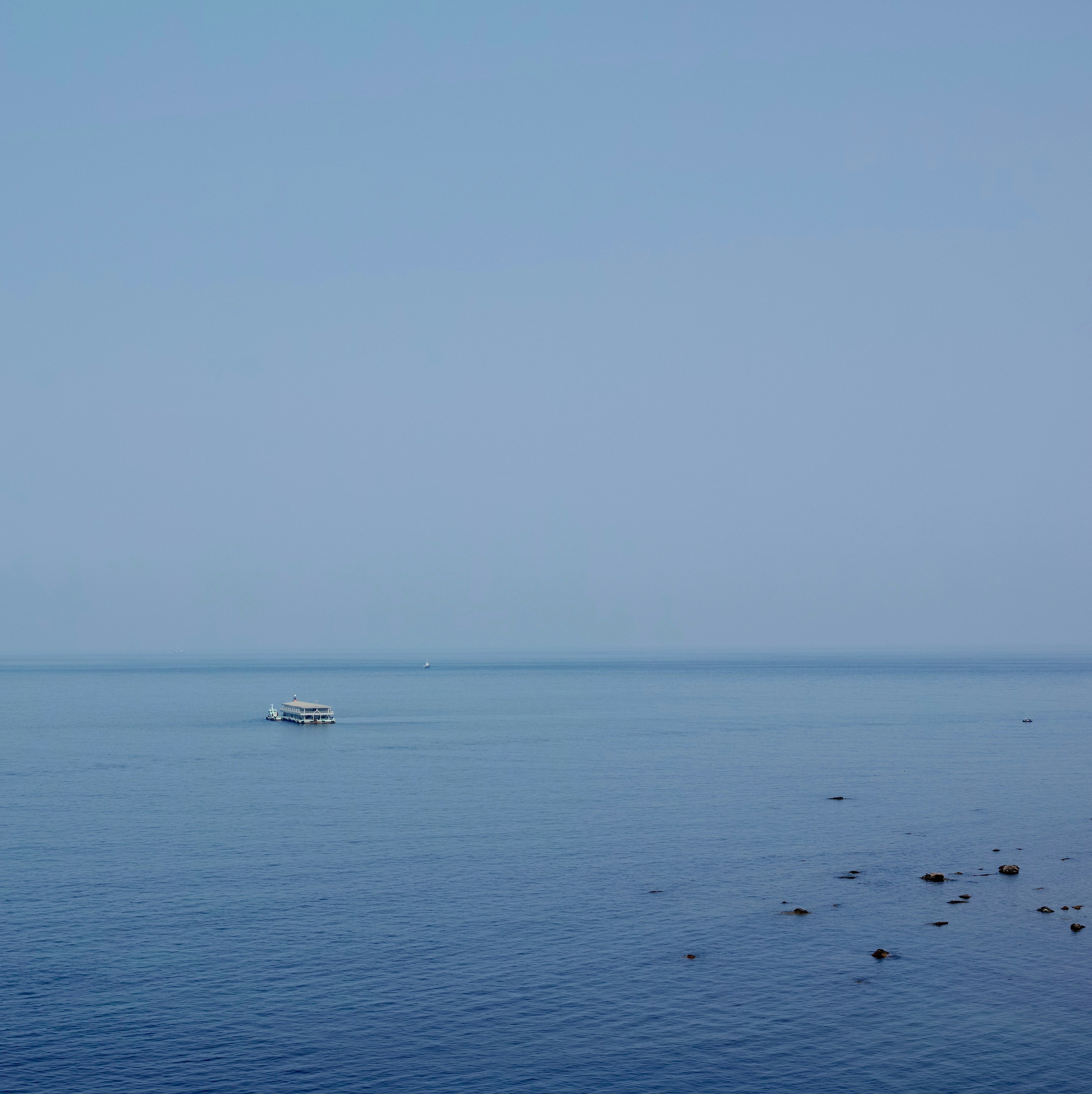 Quiet Horizon: A Small Vessel Adrift on a Vast Blue Sea