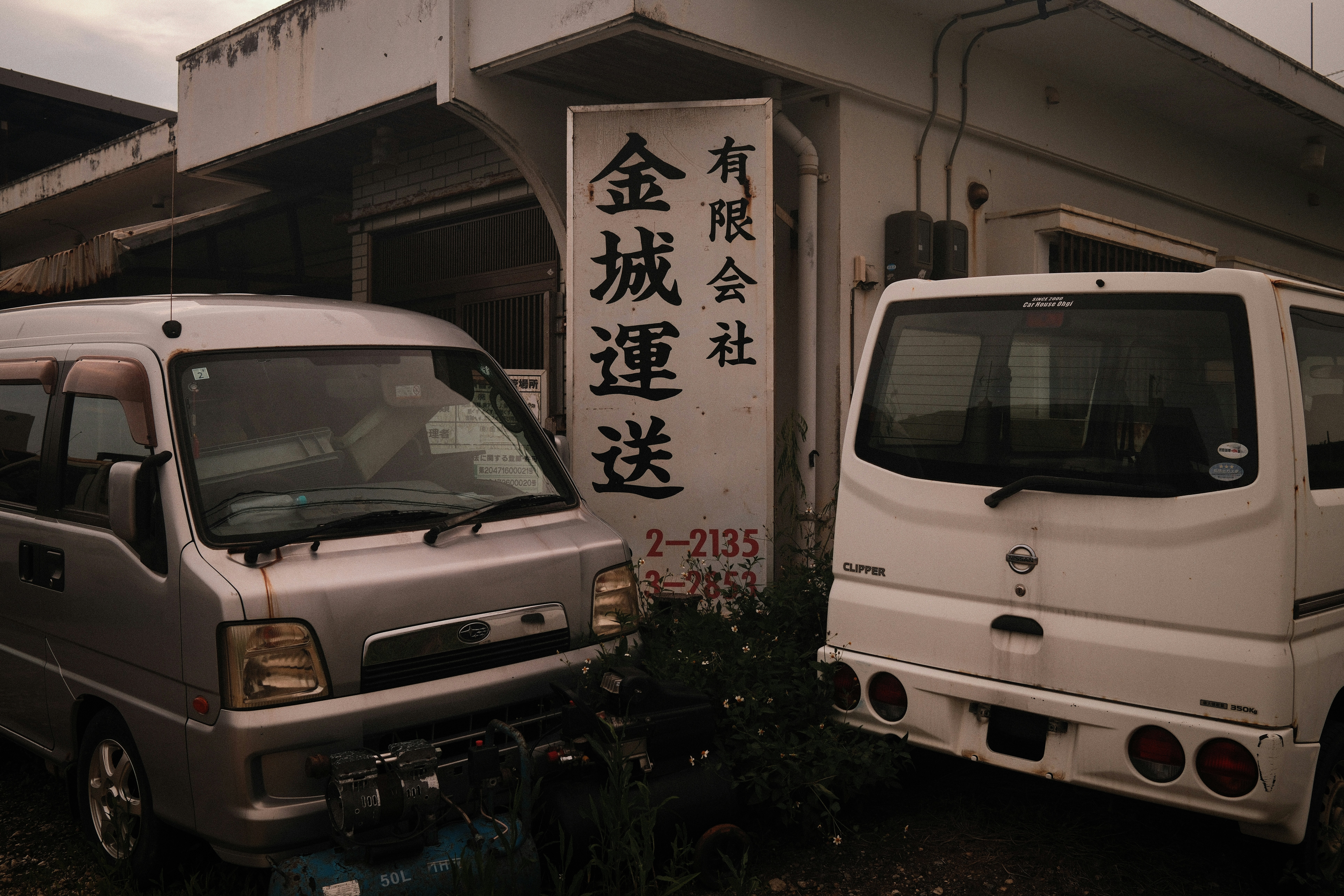 Industrial Quiet: Two Vans Framed by a Signboard