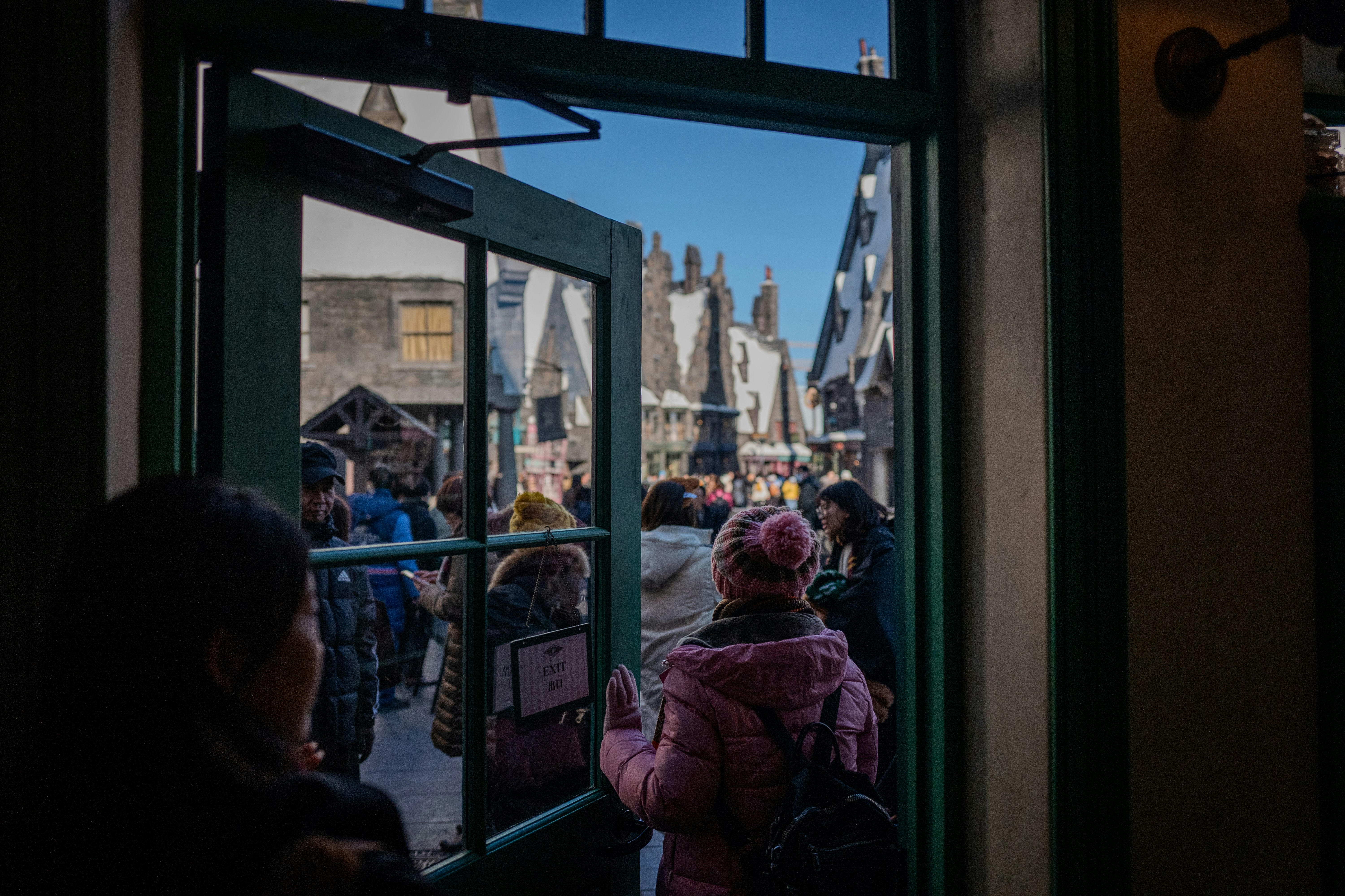 Crowd at a Dim Courtyard Gate: Winter Light Through Open Doors