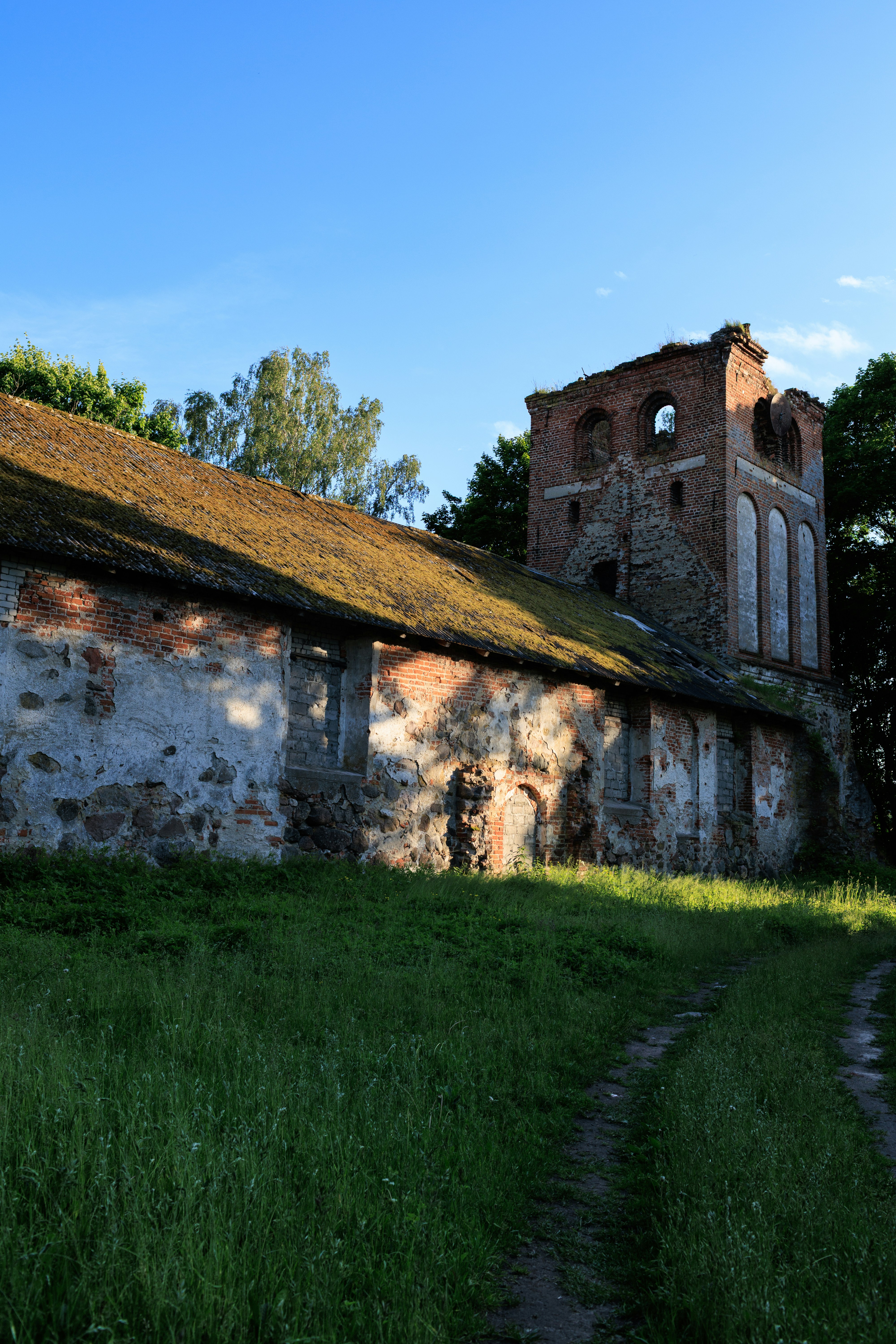 Ruined Bell Tower Above an ivy-draped brick and plaster barn at dusk
