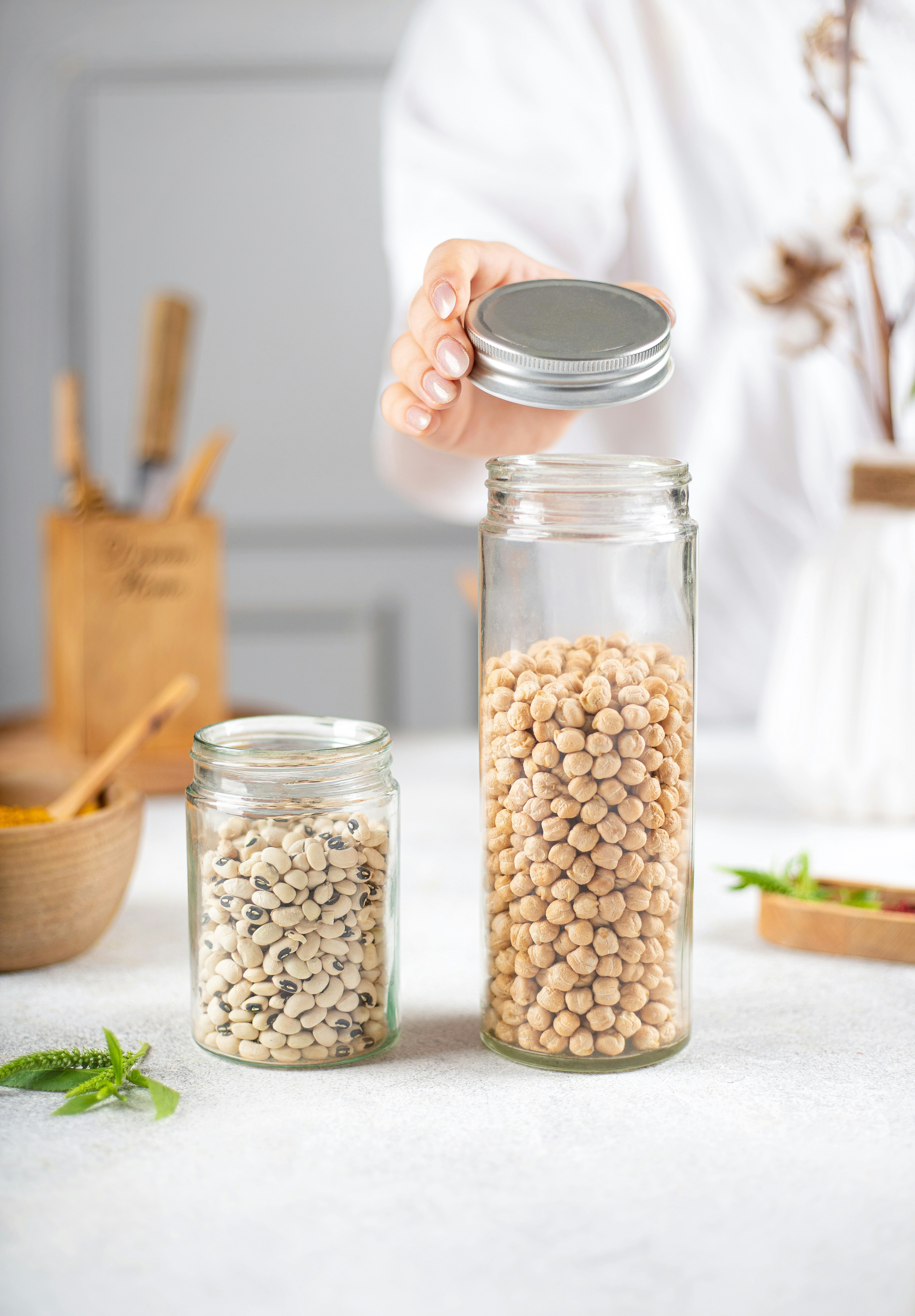 Seed Jar Symphony: A Hand Dims the Lid Over a Row of Glass Canisters