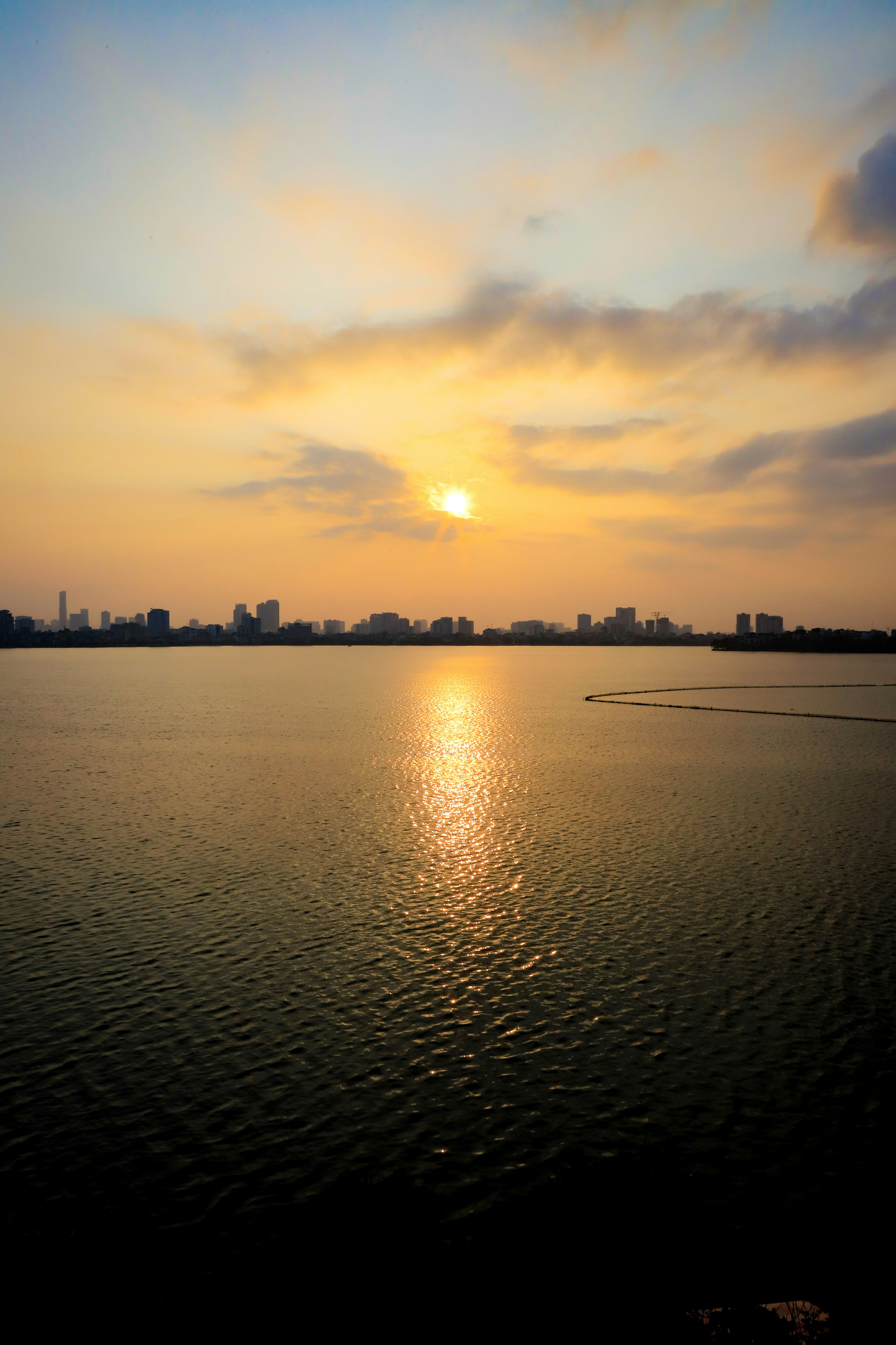 Sunlit Waterfront at Dusk: A Silhouette of City Peaks and a Glimmering Core