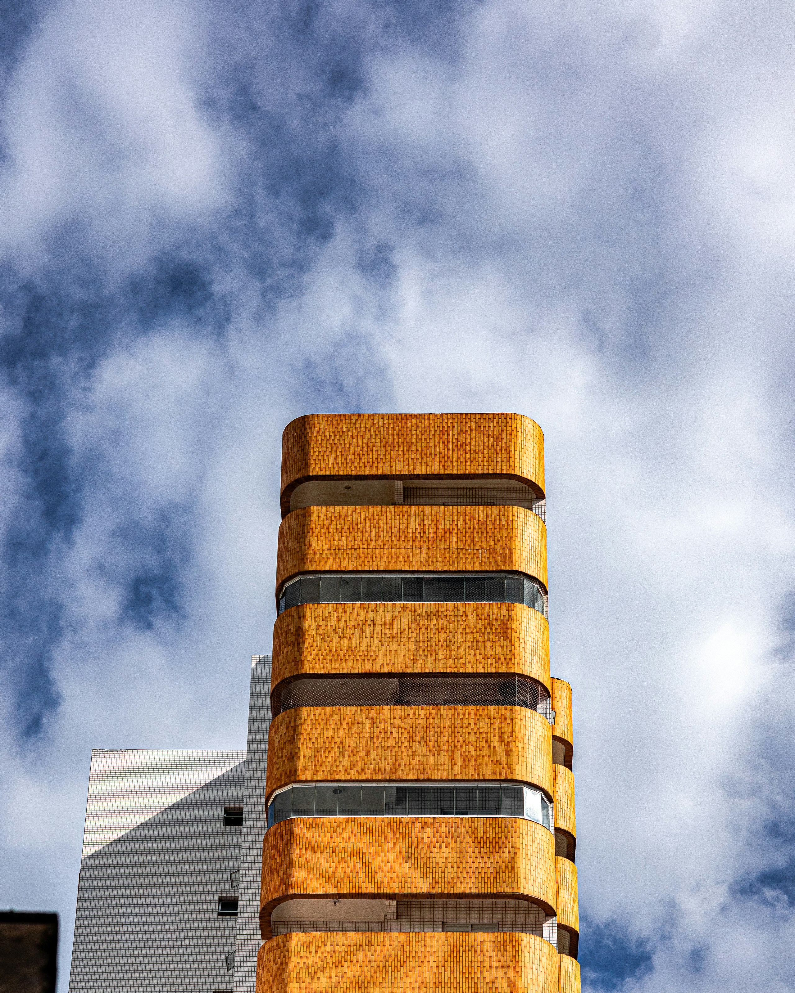 Golden Cantilevered Ribbons: A Tower of Orange Curves Against a Blue Sky
