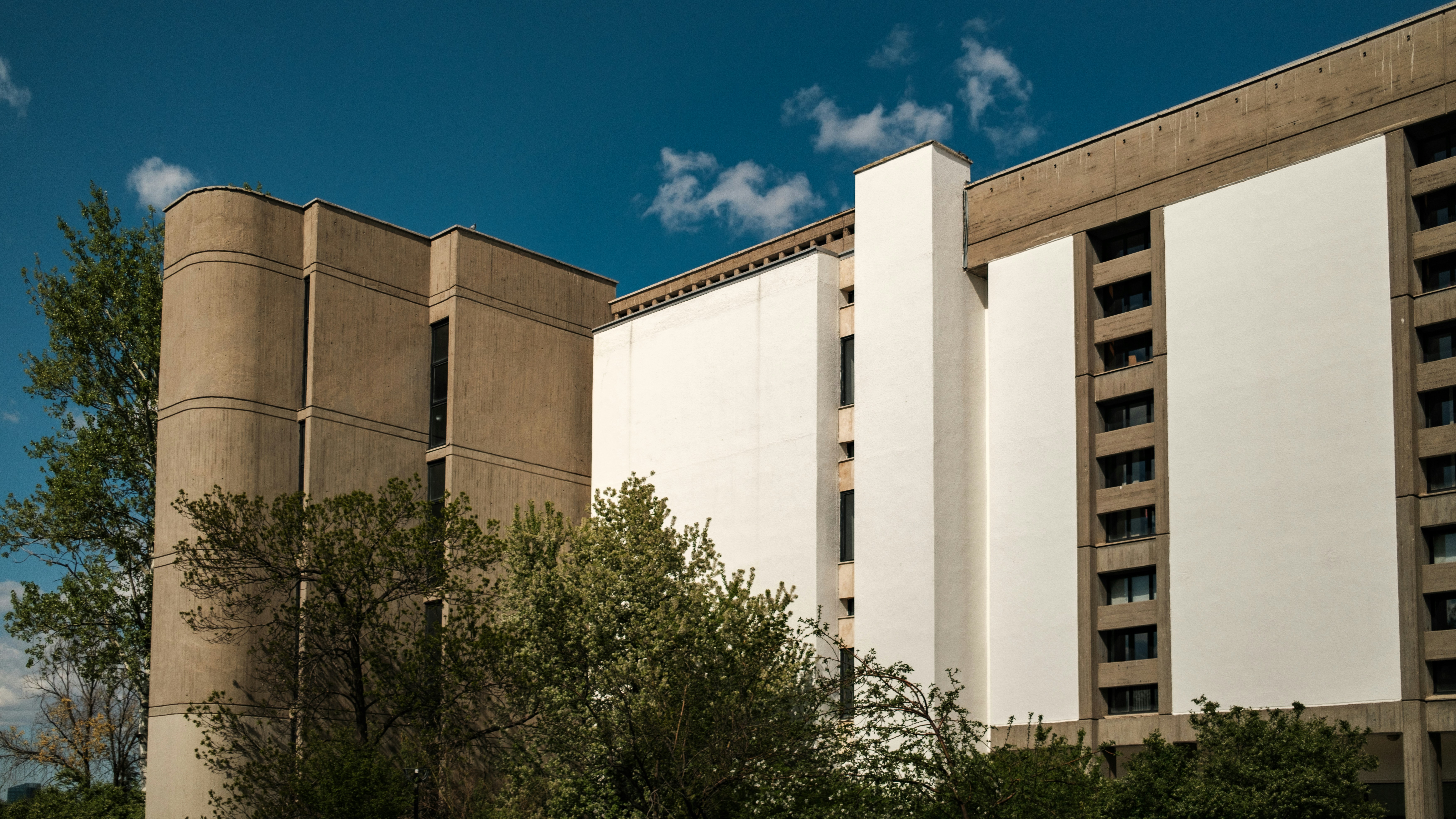 Modern building with brown concrete, white facade, and blue sky.