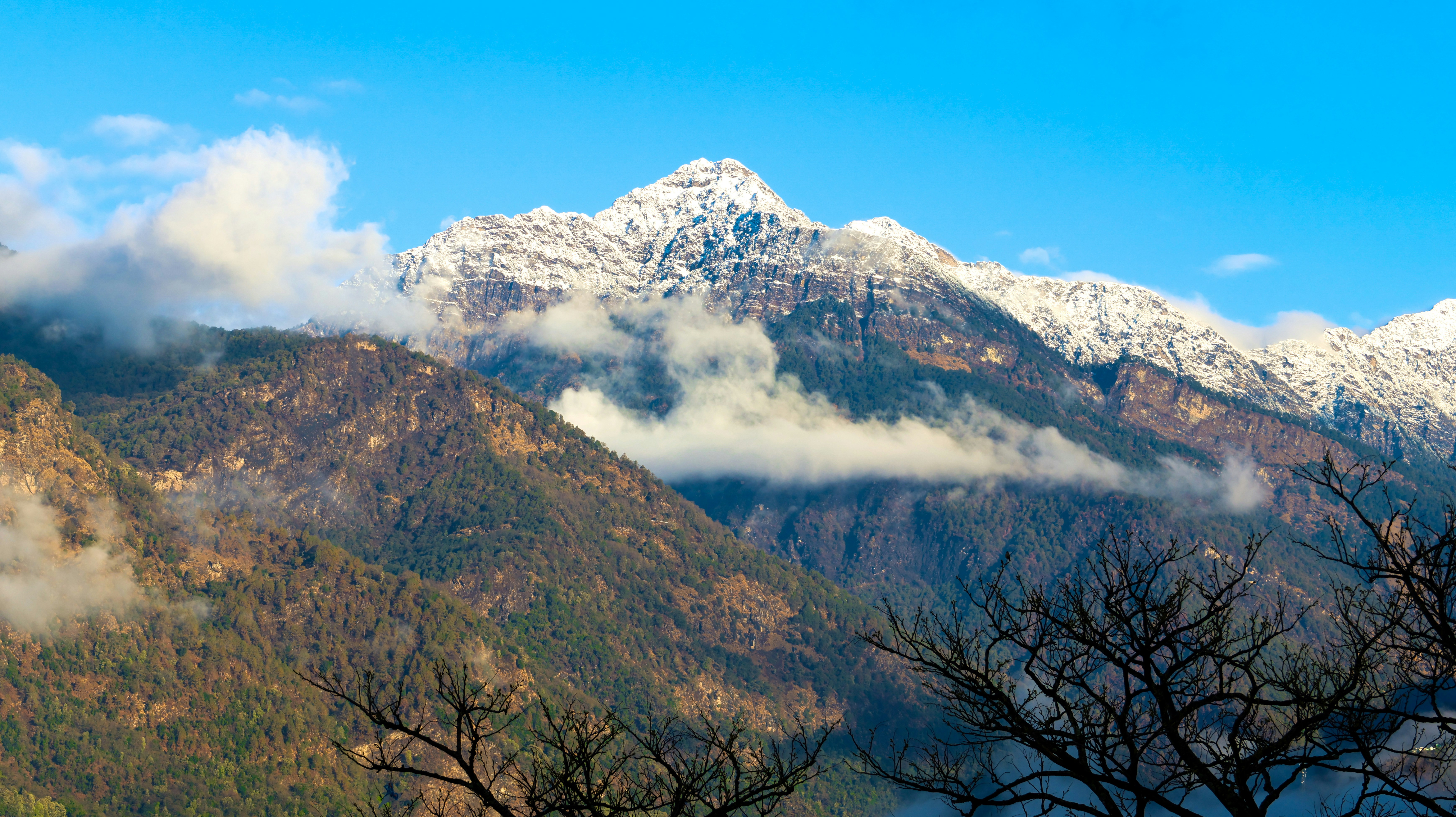 Snow-capped Peak Pierced by Clouds Over Autumn Valleys