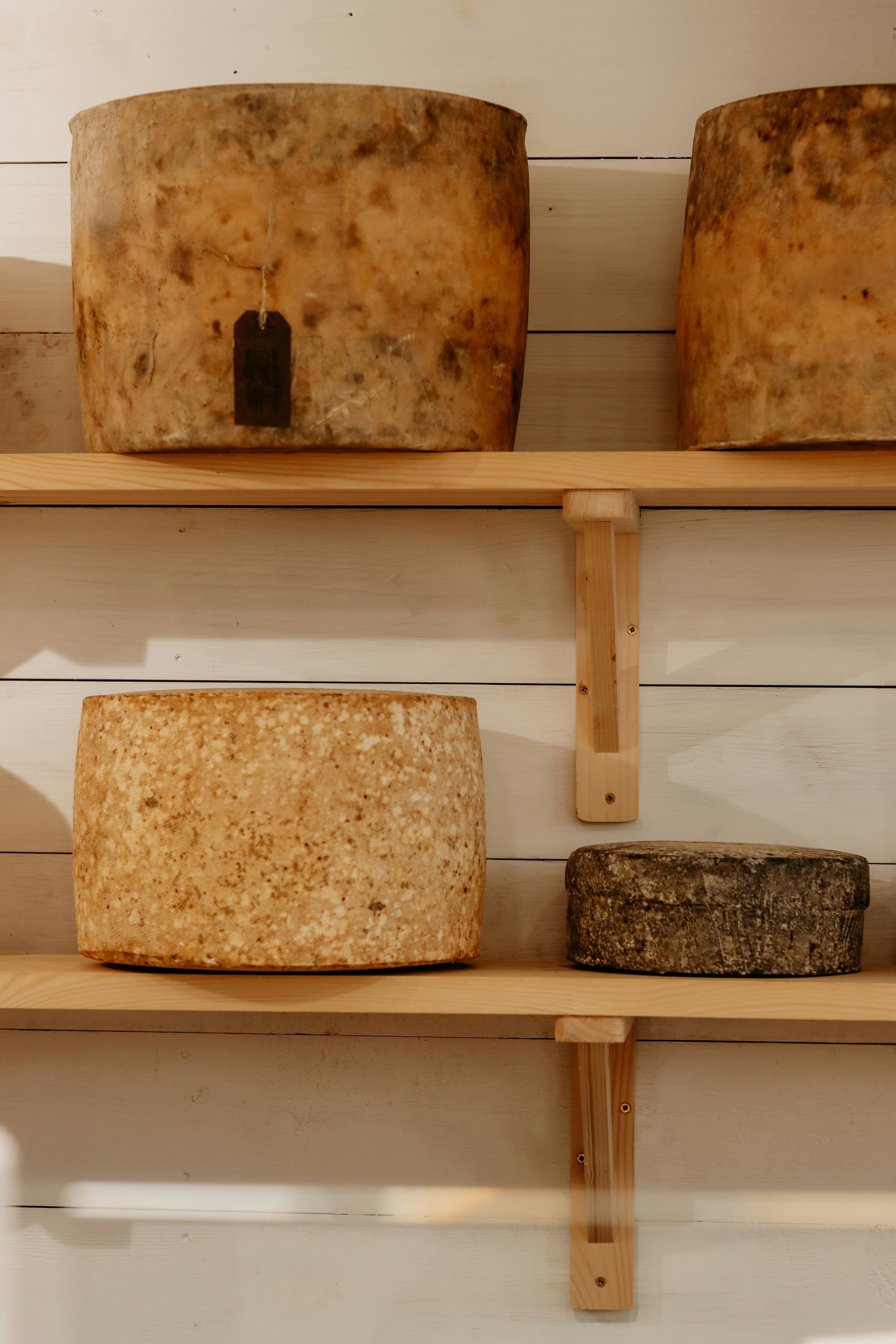 A Quiet Gallery of Rustic Cheeses on Wooden Shelves