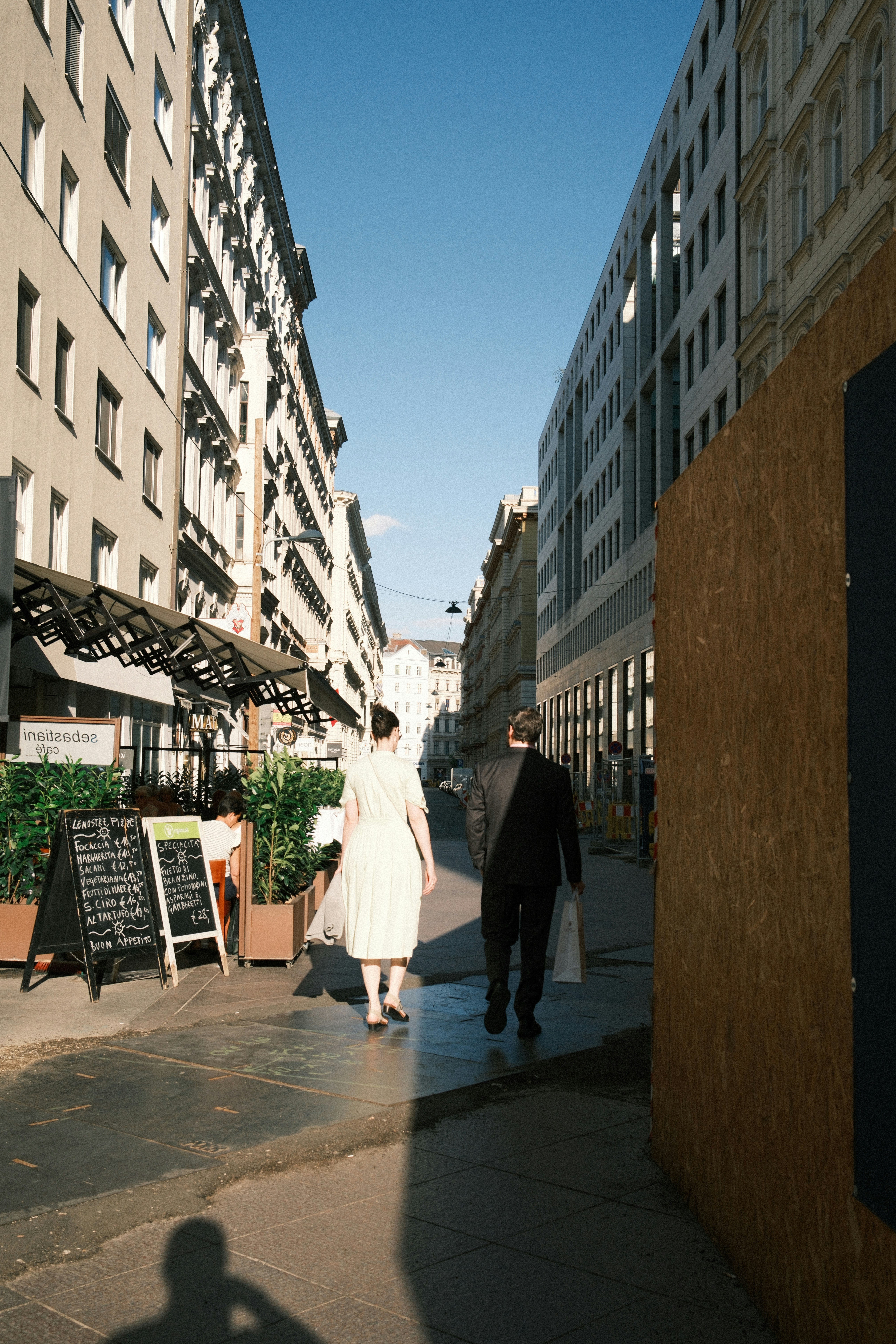A Quiet City Walk: Two Figures in Sunlit Street