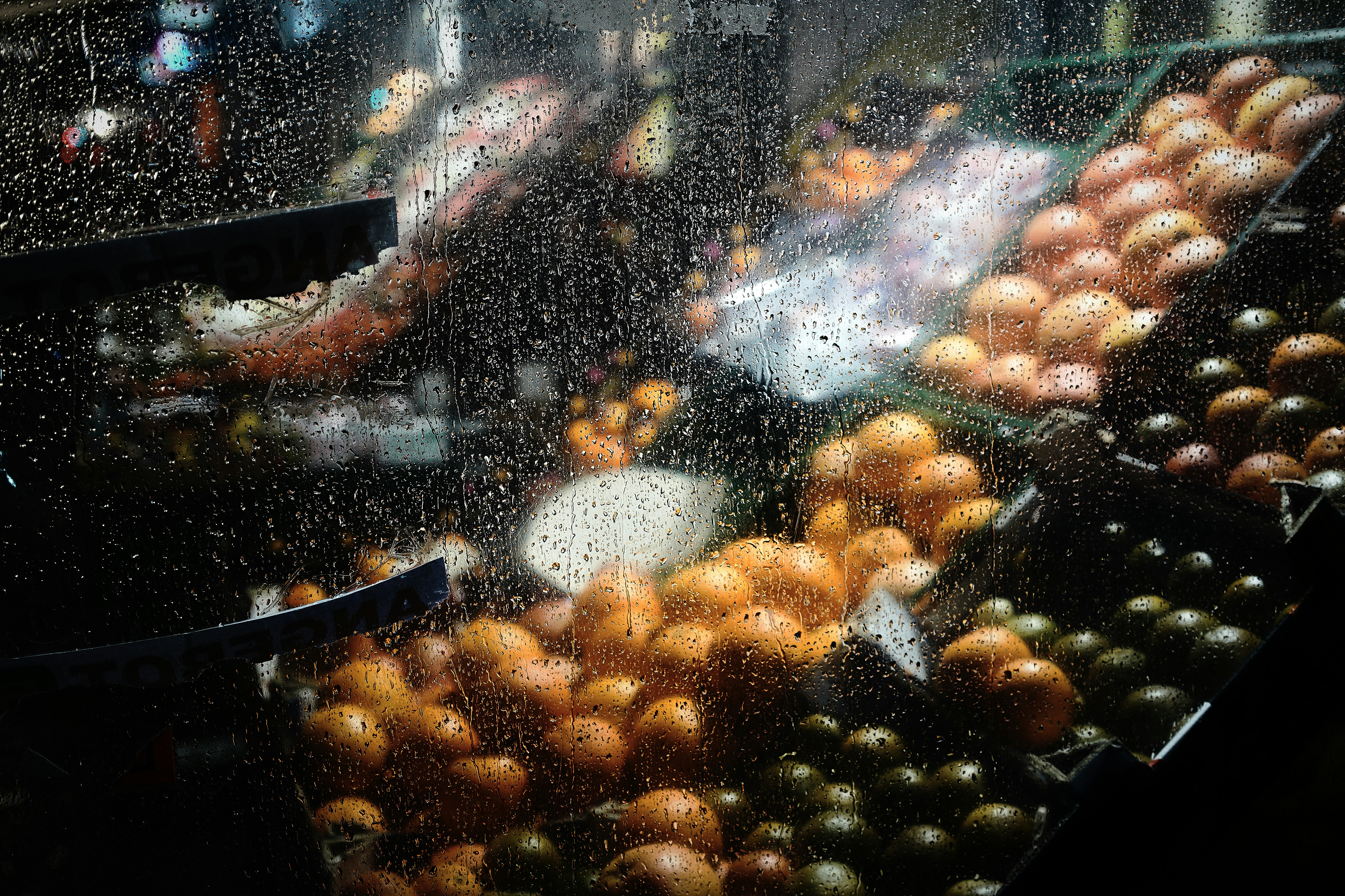 Rain-Streaked Display of Citrus and Produce
