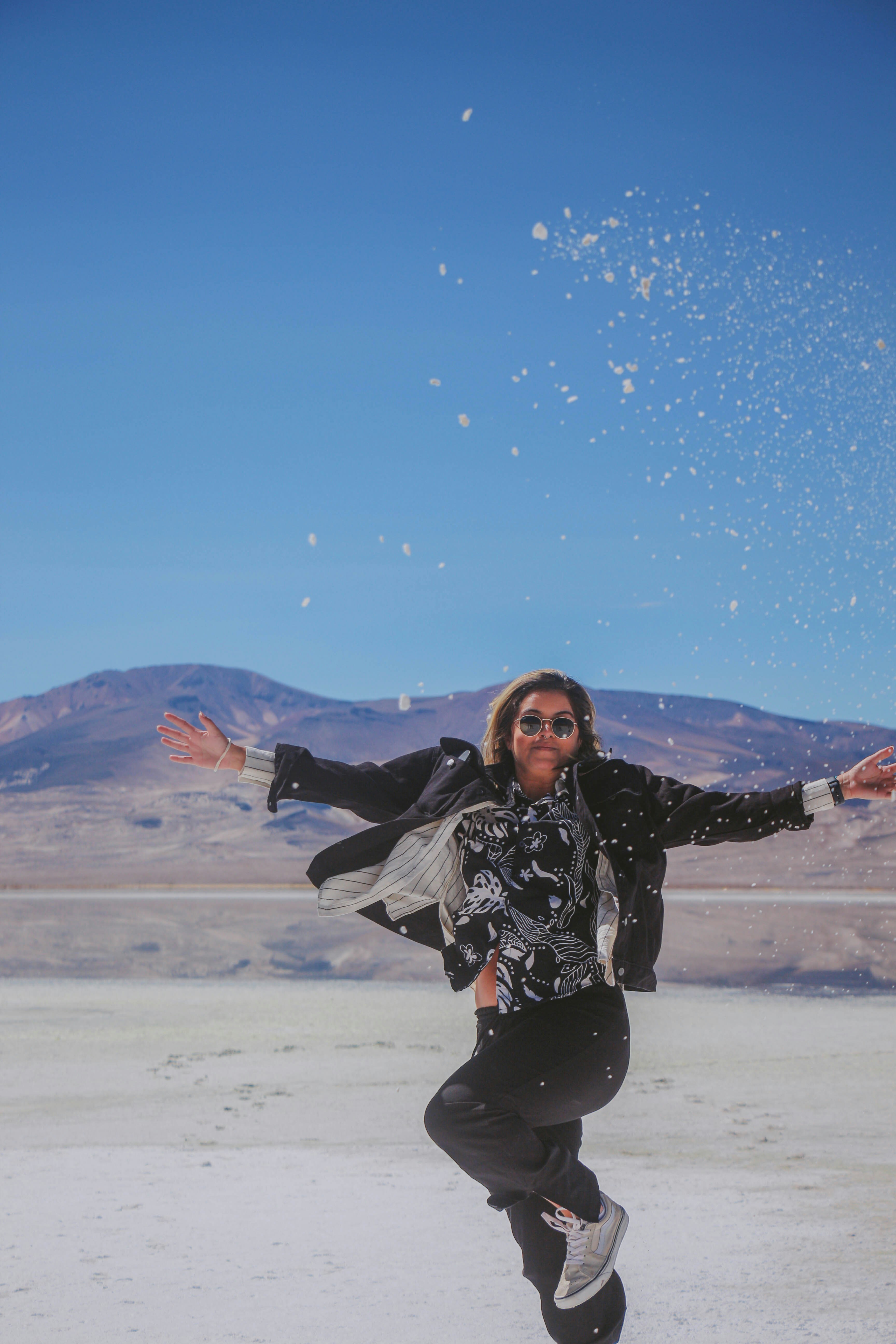 Joyful leap on a sunlit saline plain under a clear blue sky