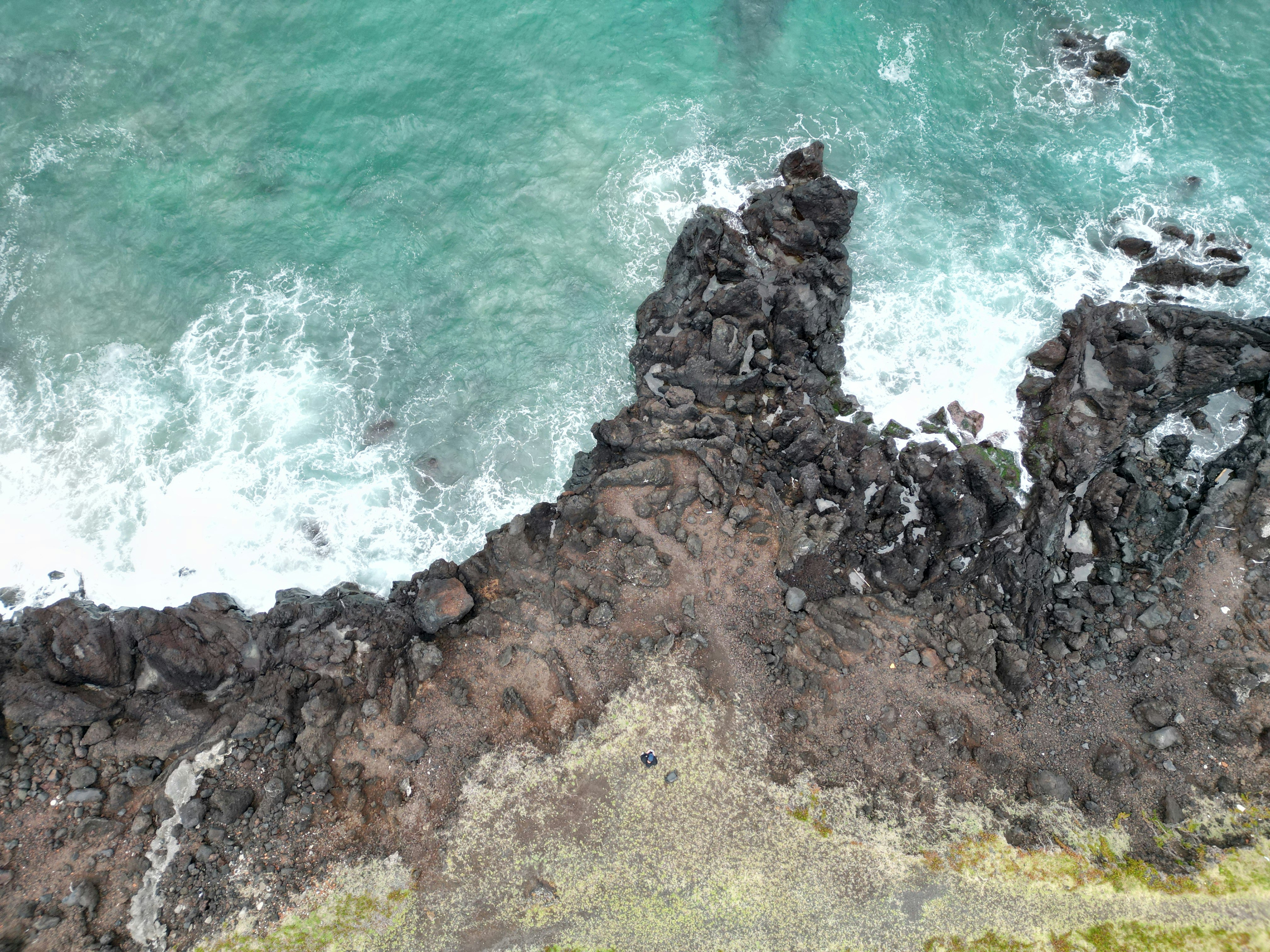 Coastal Ridge: Turquoise Sea Meets Weathered Black Rock