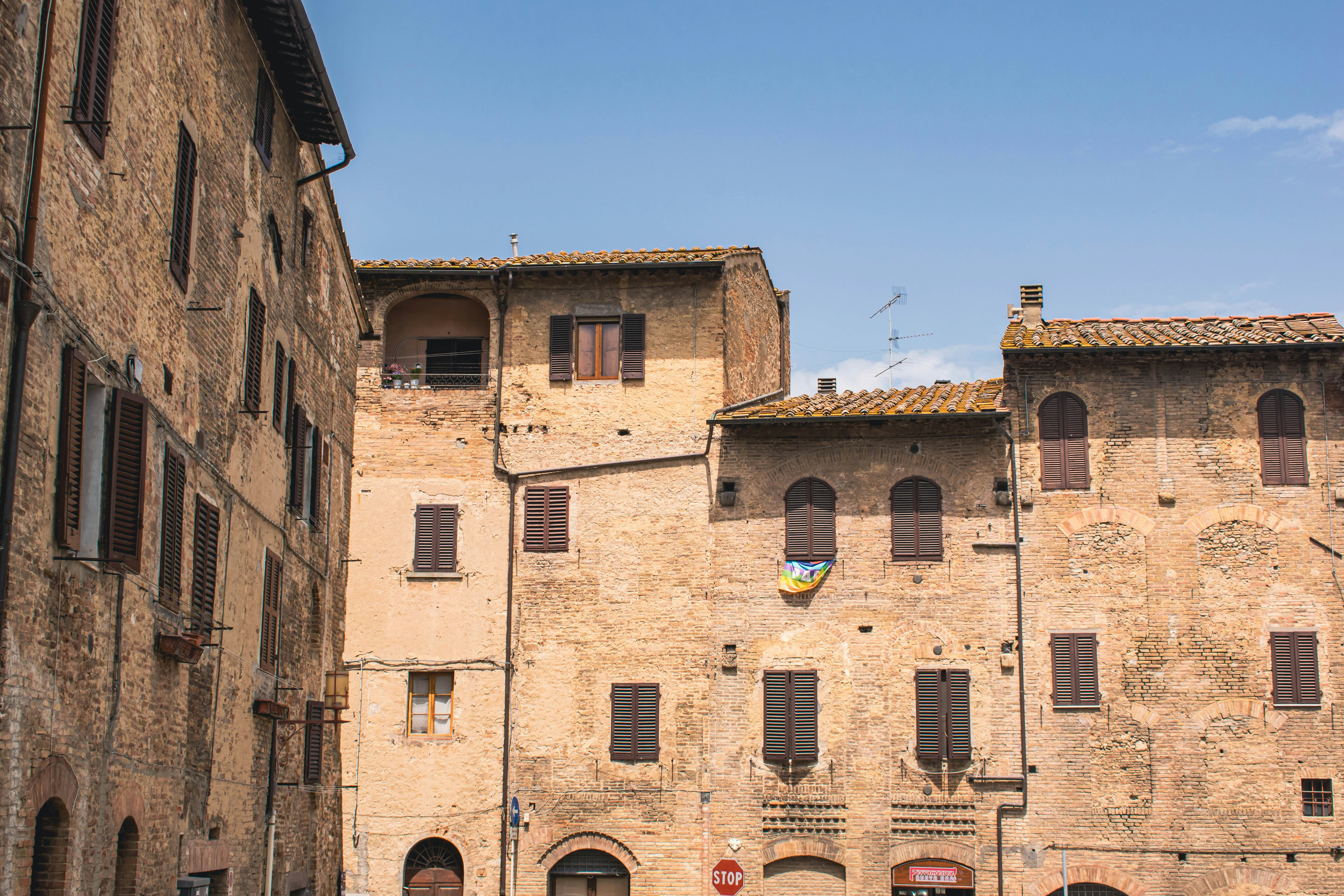Sunlit Tuscan Facades: A Quiet Urban Study of Brick and Window Shutters
