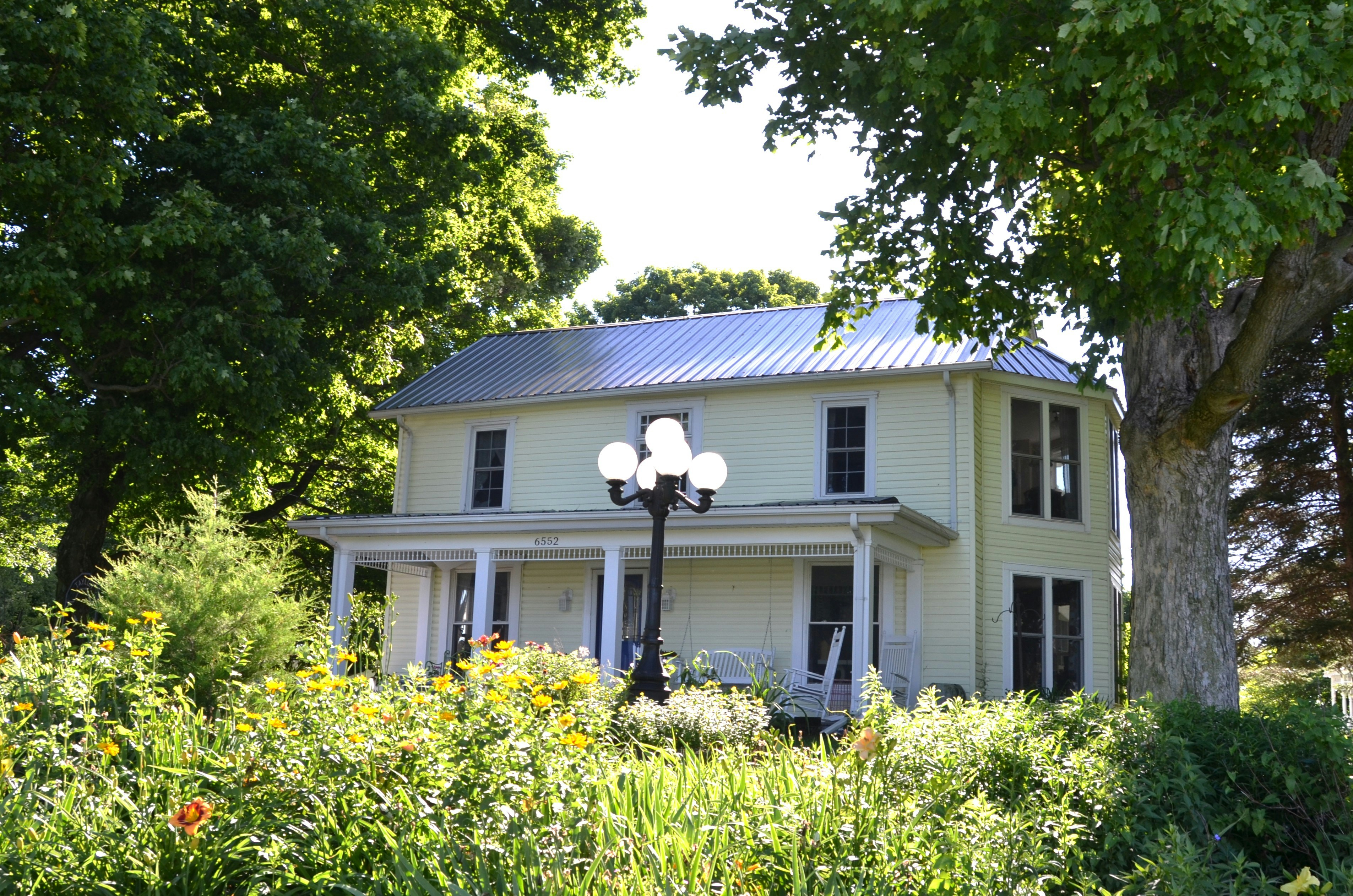 Sunlit Colonial House Surrounded by Colorful Garden in Full Bloom