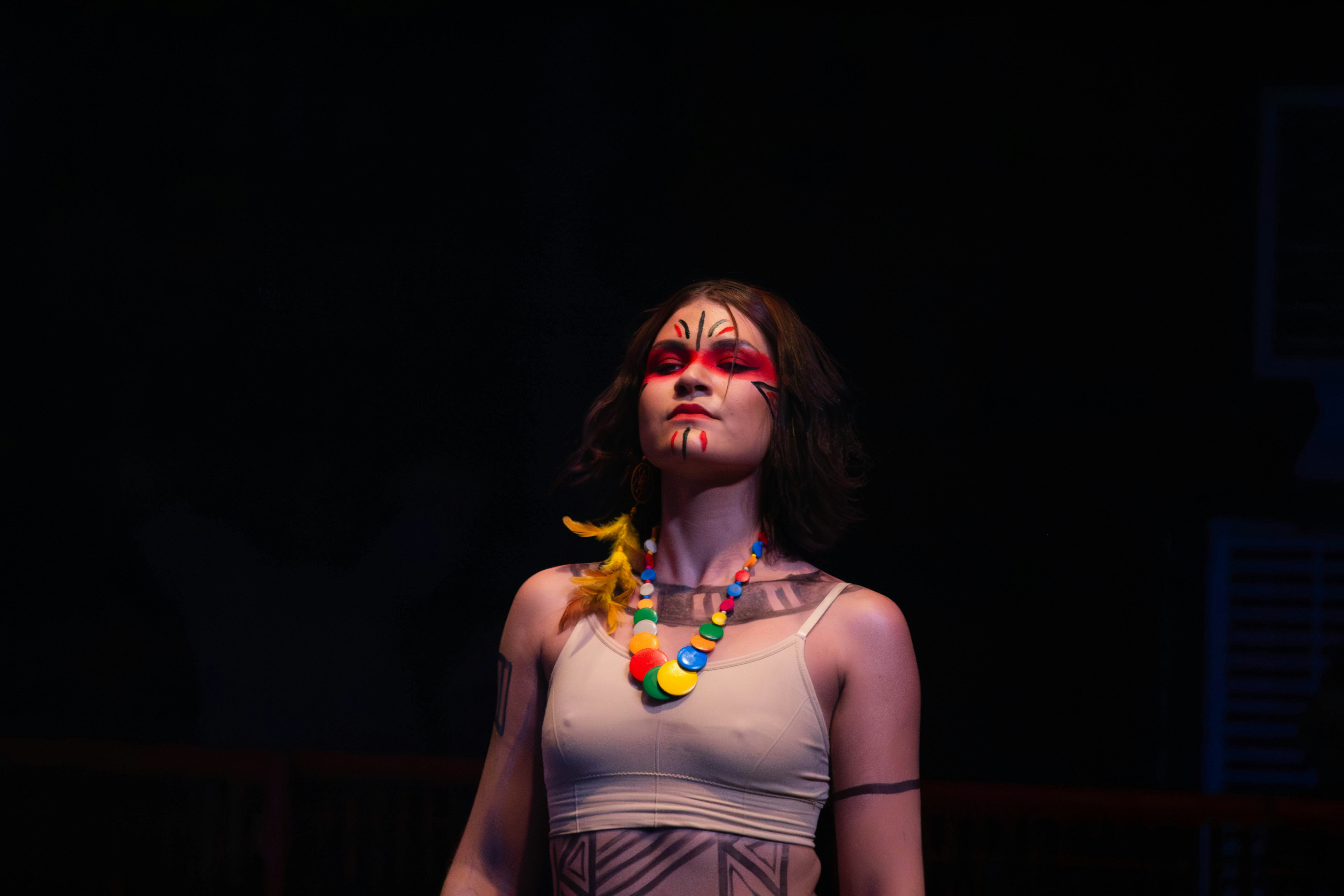 Face paint and necklace under spotlight: a stage portrait