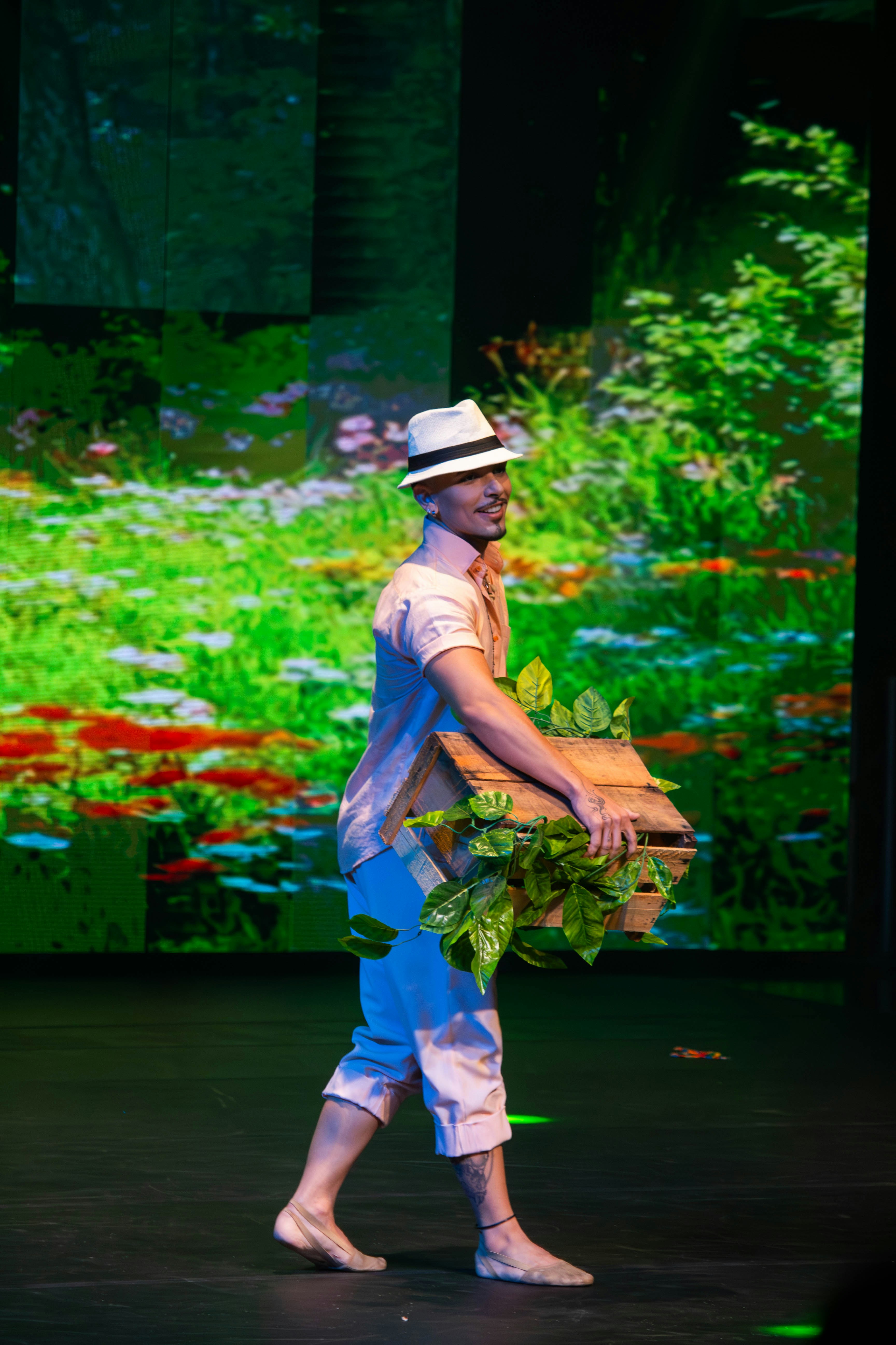 Market Gardener in a Lush Backdrop: A Dancer Carries a Wooden Crate