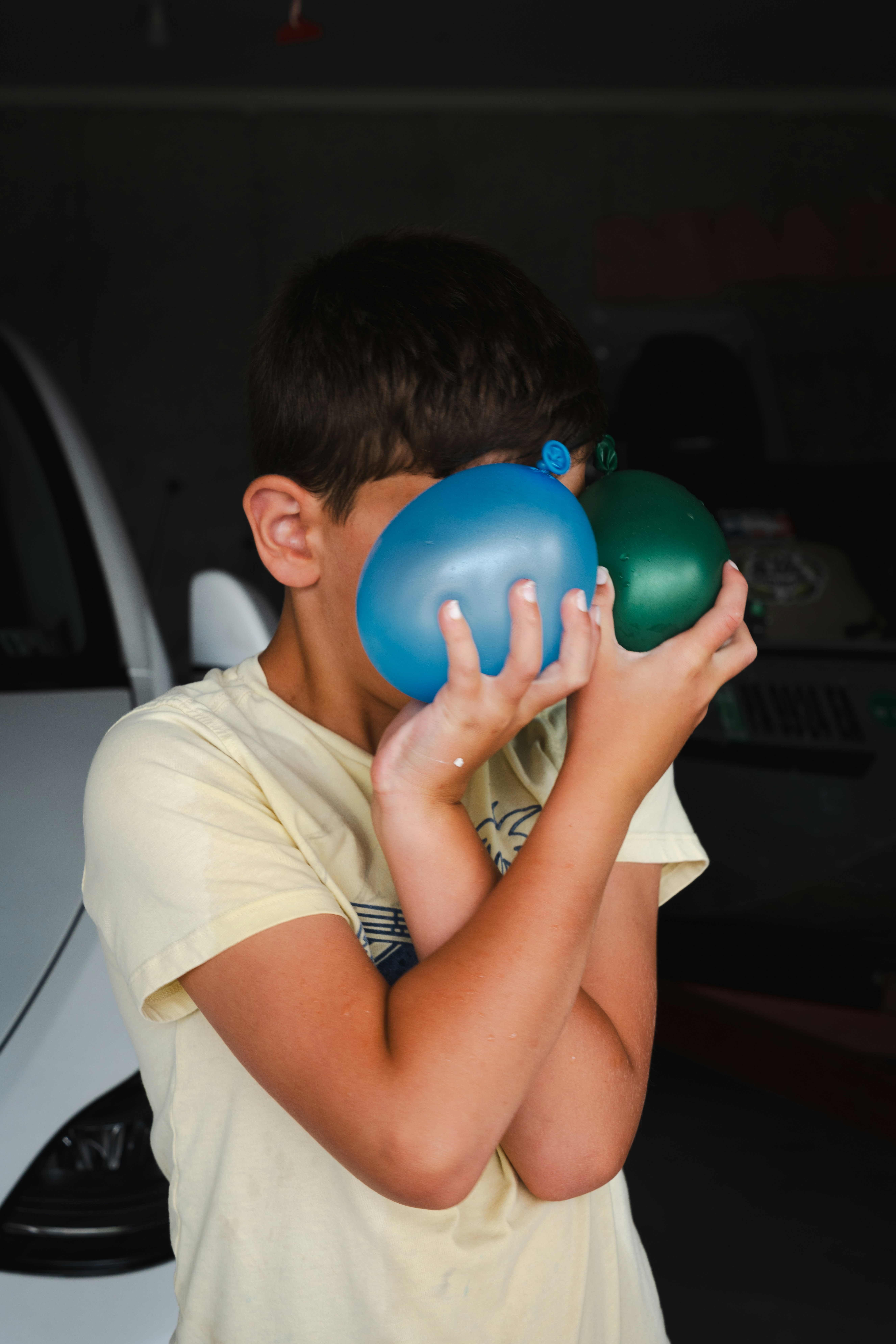 Boy holding blue and green water balloons.