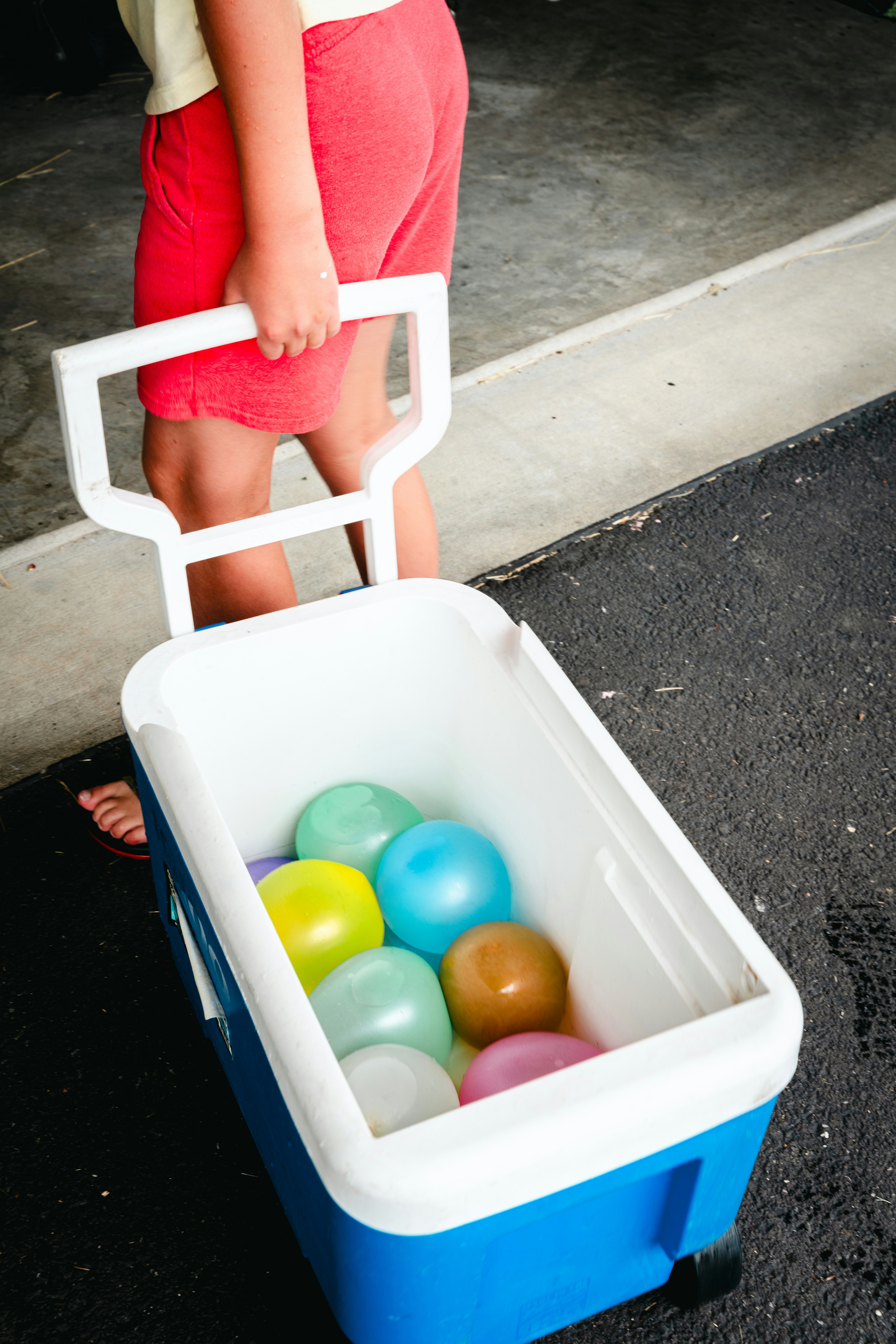 A child pulls a cooler filled with colorful water balloons.