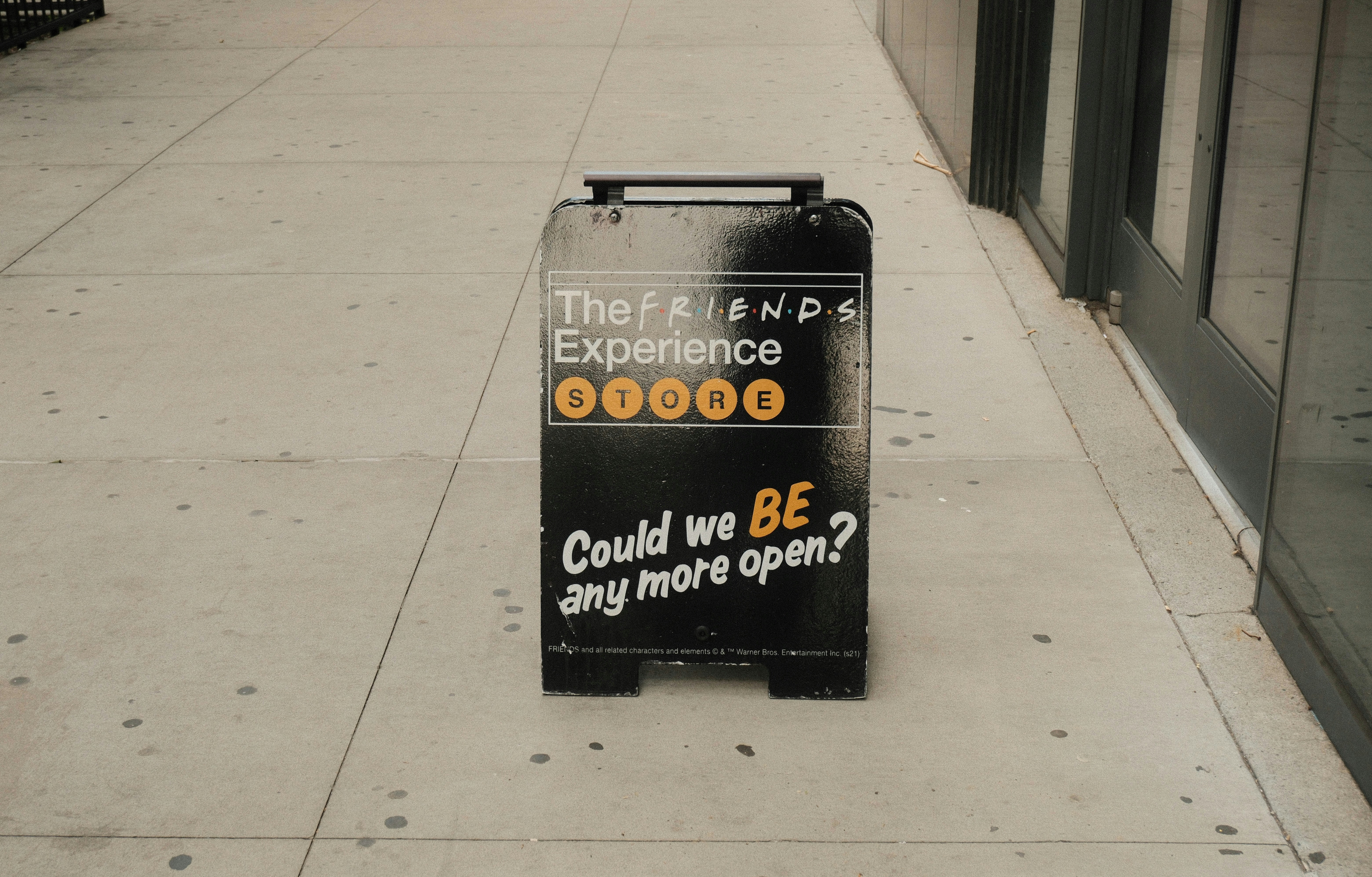 The friends experience sign on a city sidewalk.