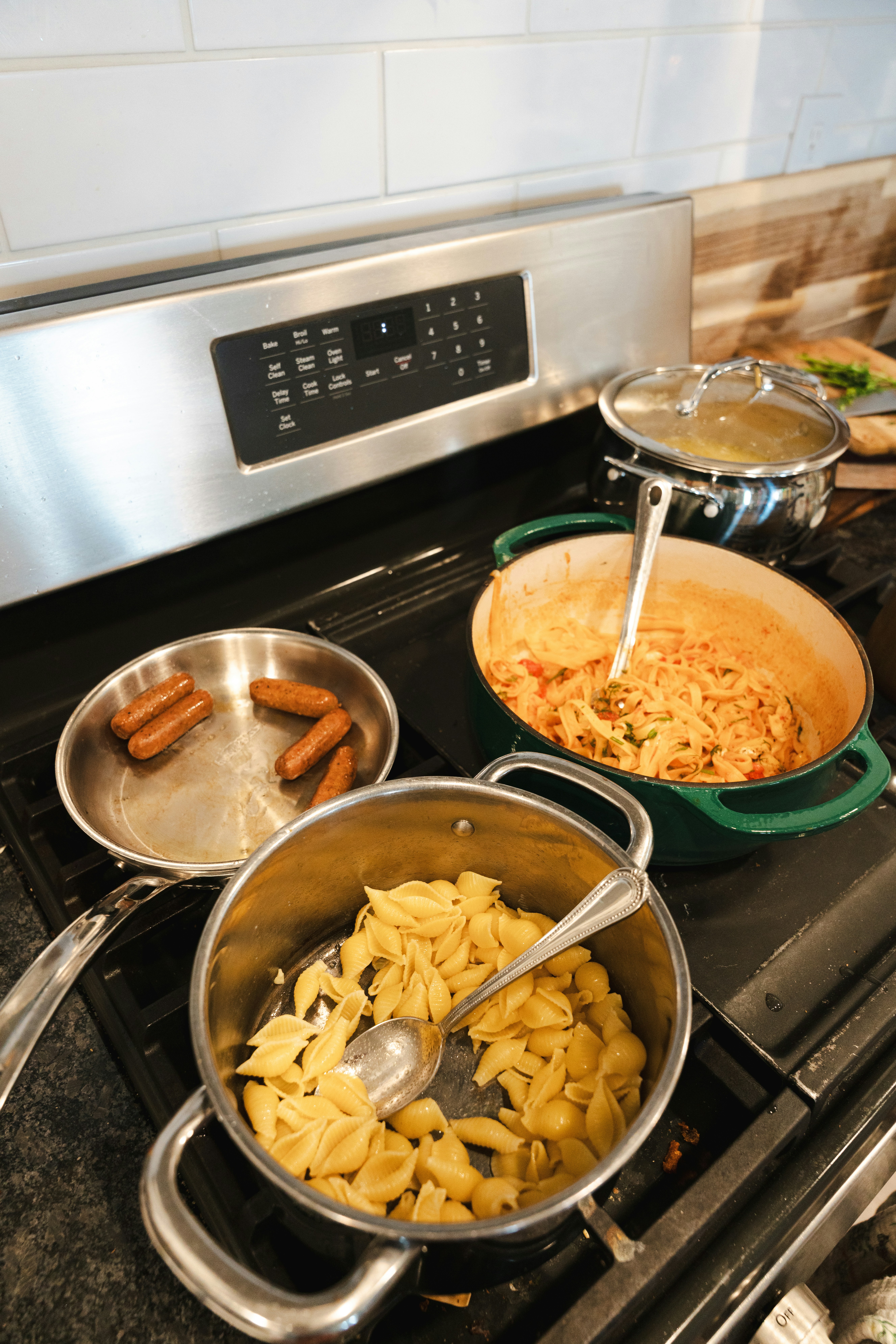 Stovetop Symphony: Pasta Pot, Sausage Skillet, and Noodles in a Busy Kitchen
