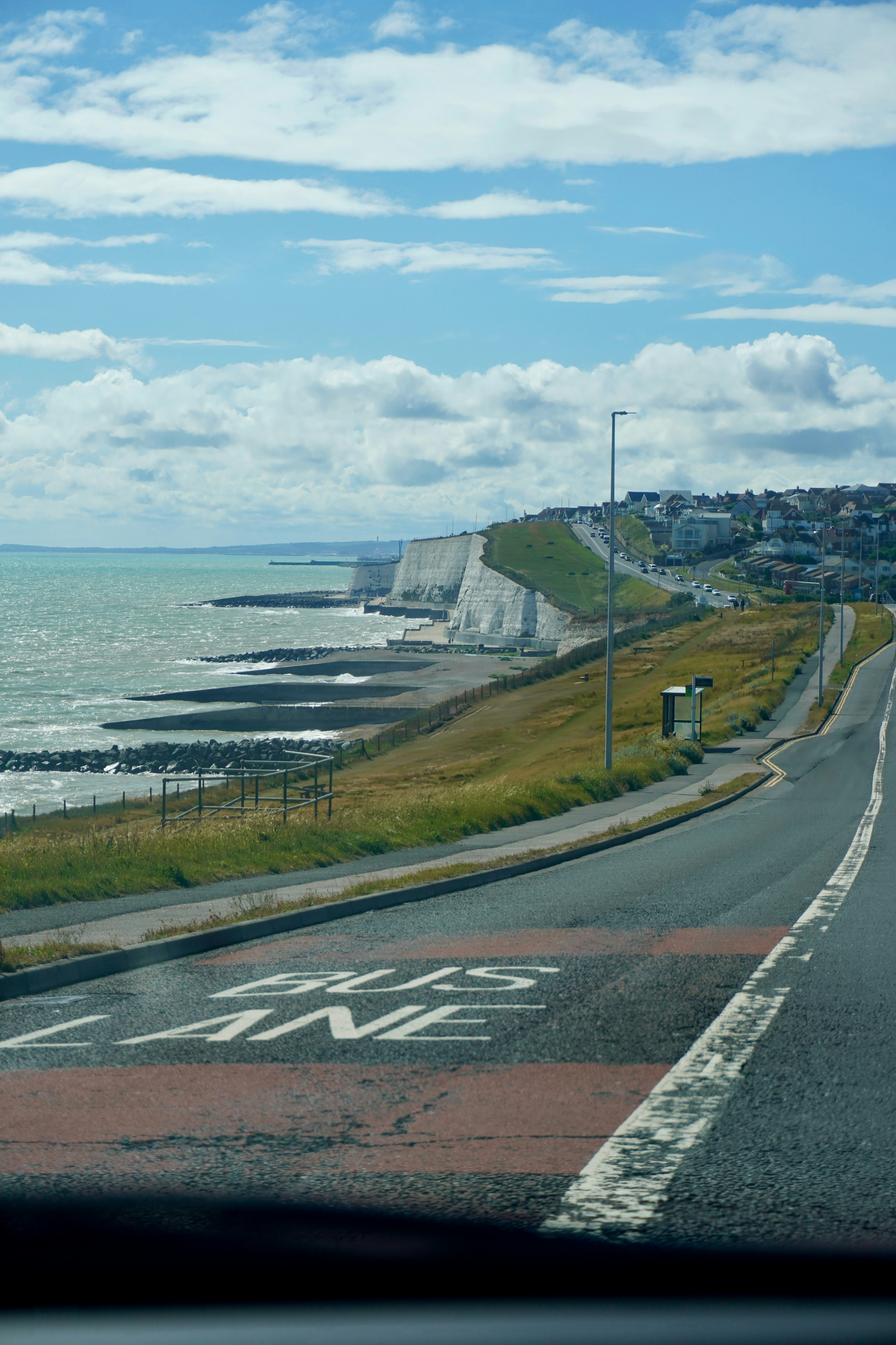Coastal Climb: Sea Wall, Road, and Distant Dwellings