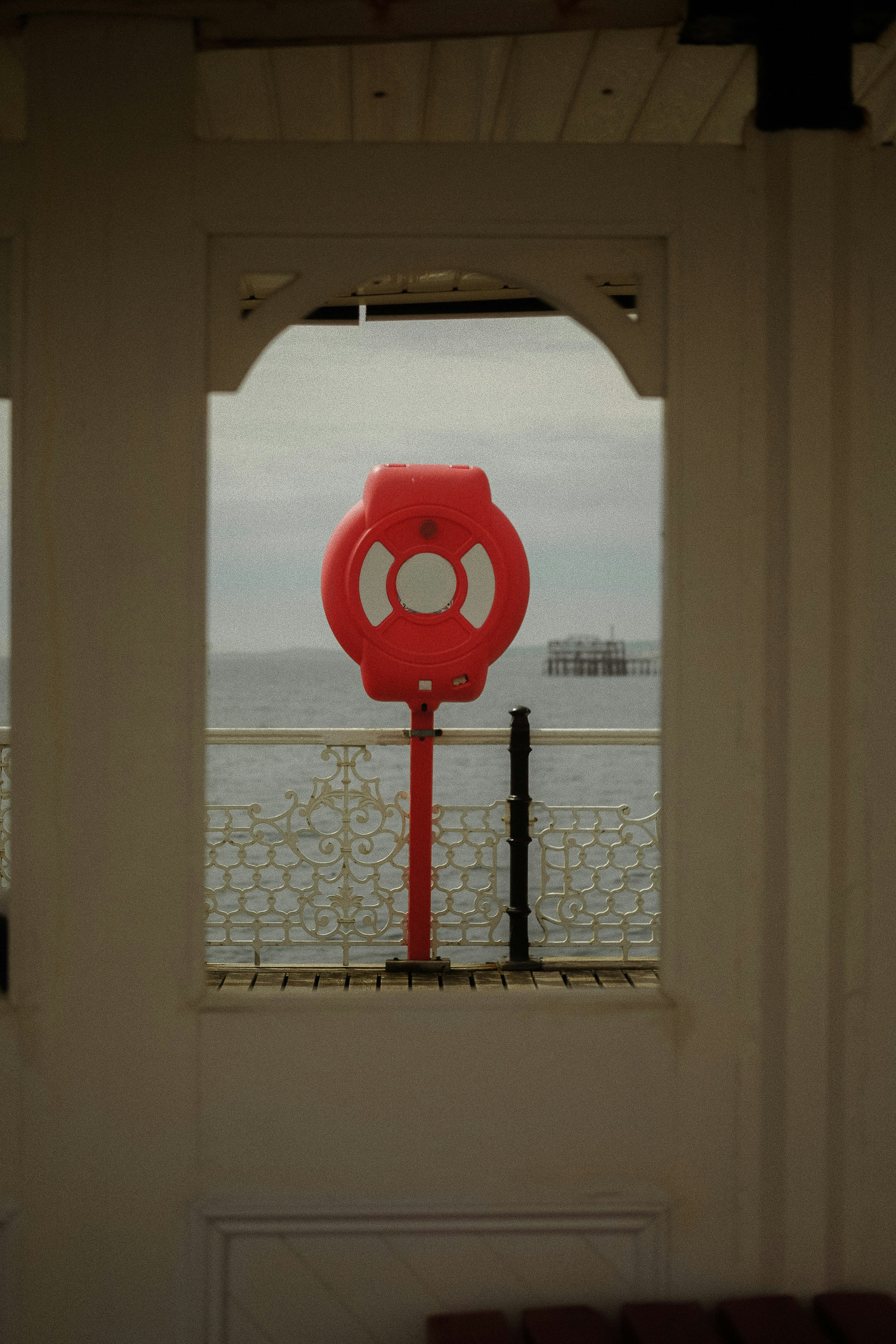 Red lifebuoy framed by a seaside archway