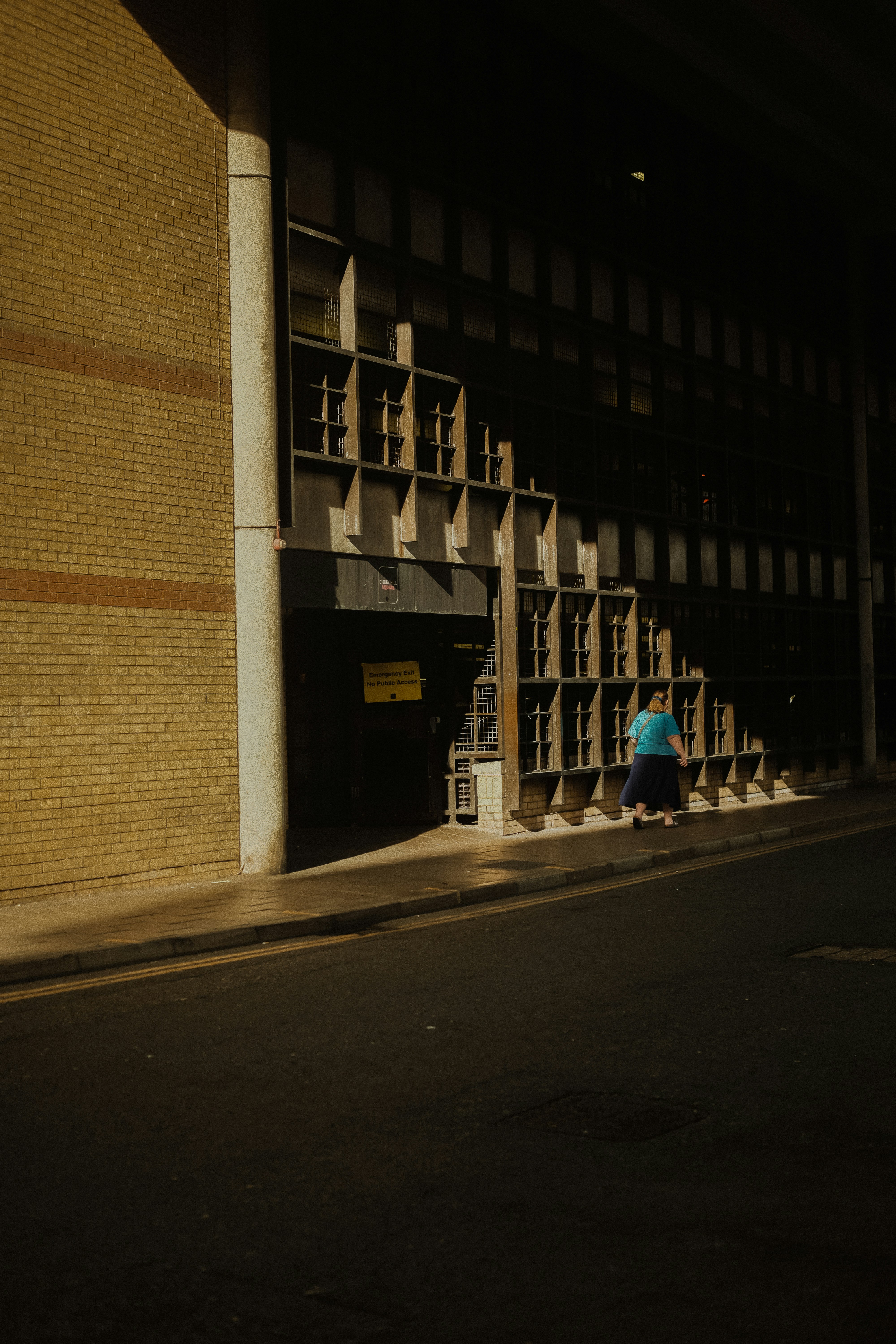 Blue-Jacketed Figure Beneath Gridwork Shadows