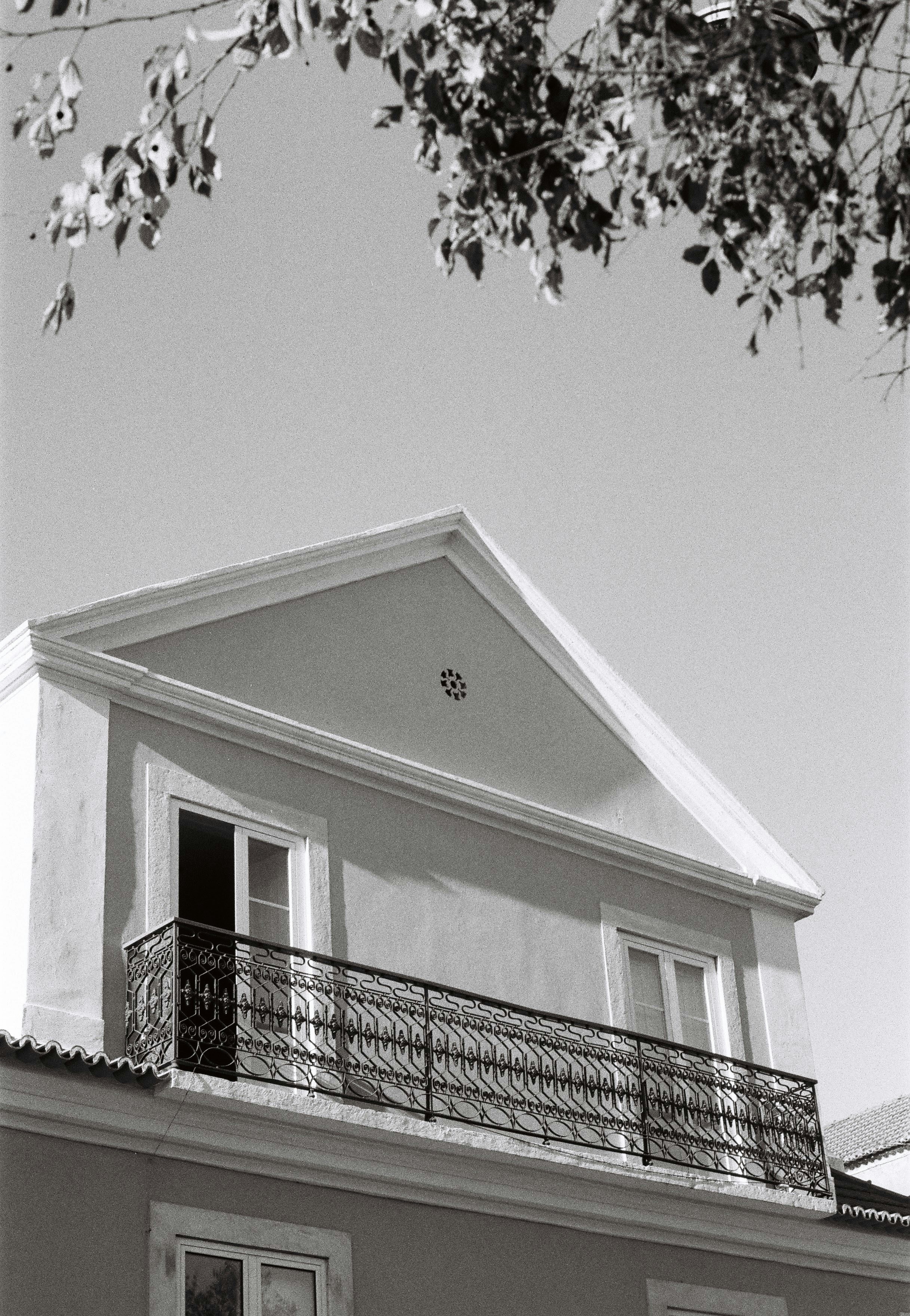 Elegant Gable and Balcony: Monochrome Facade Under Cedar Canopy