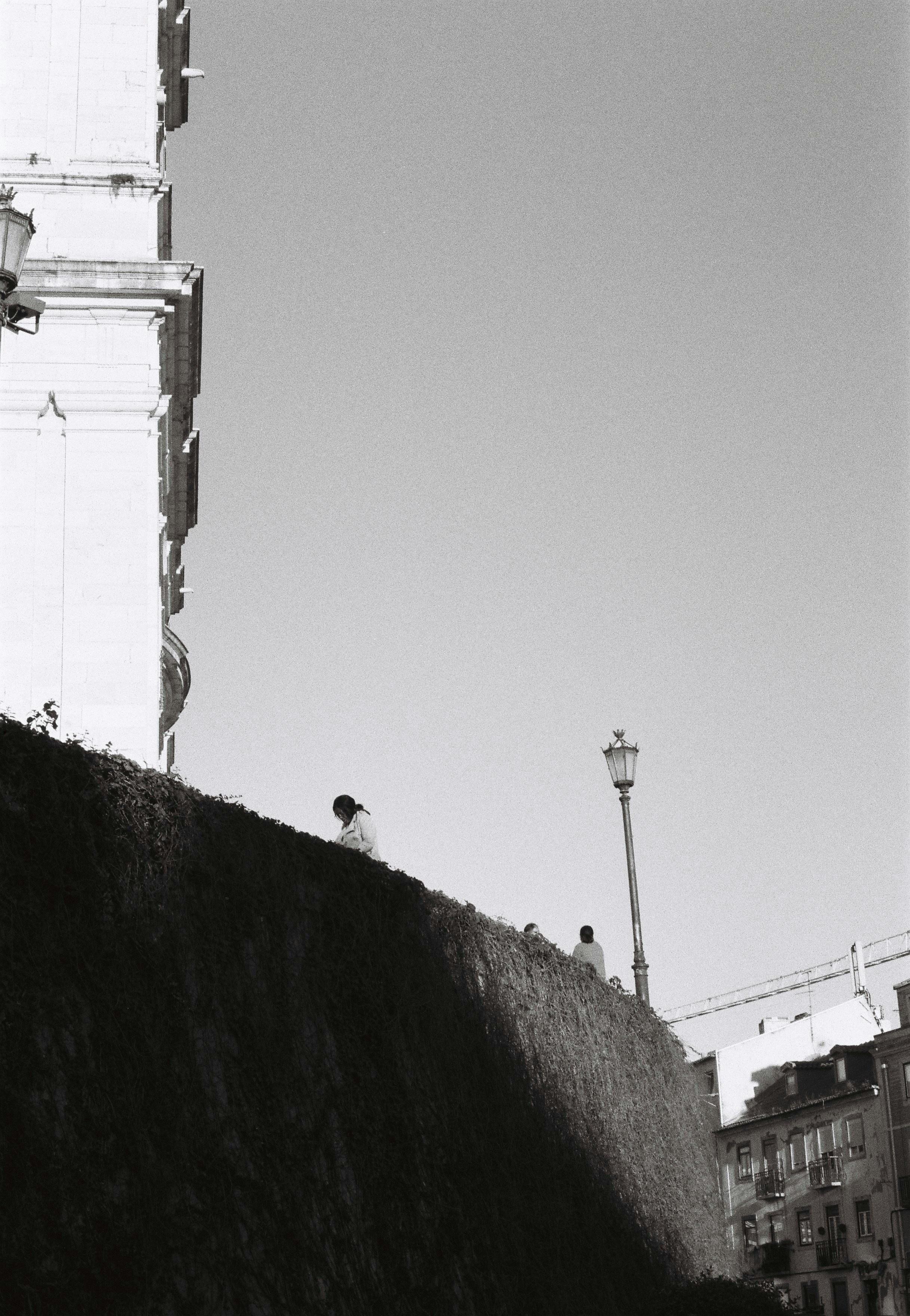 Silhouette on the Clifftop: Quiet Figures Beneath an Urban Sky