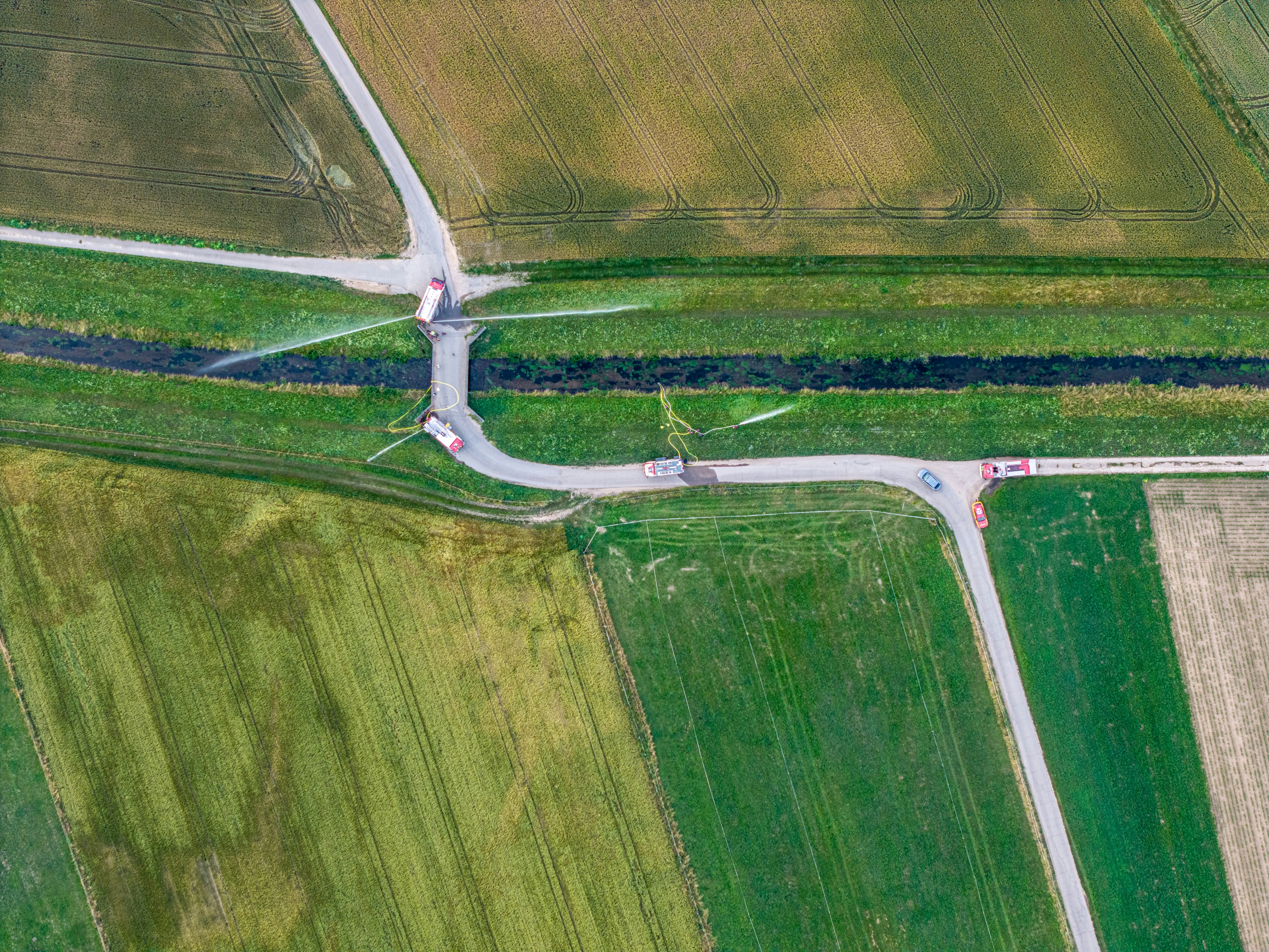 Overhead view of farmland with a canal and connecting roads.