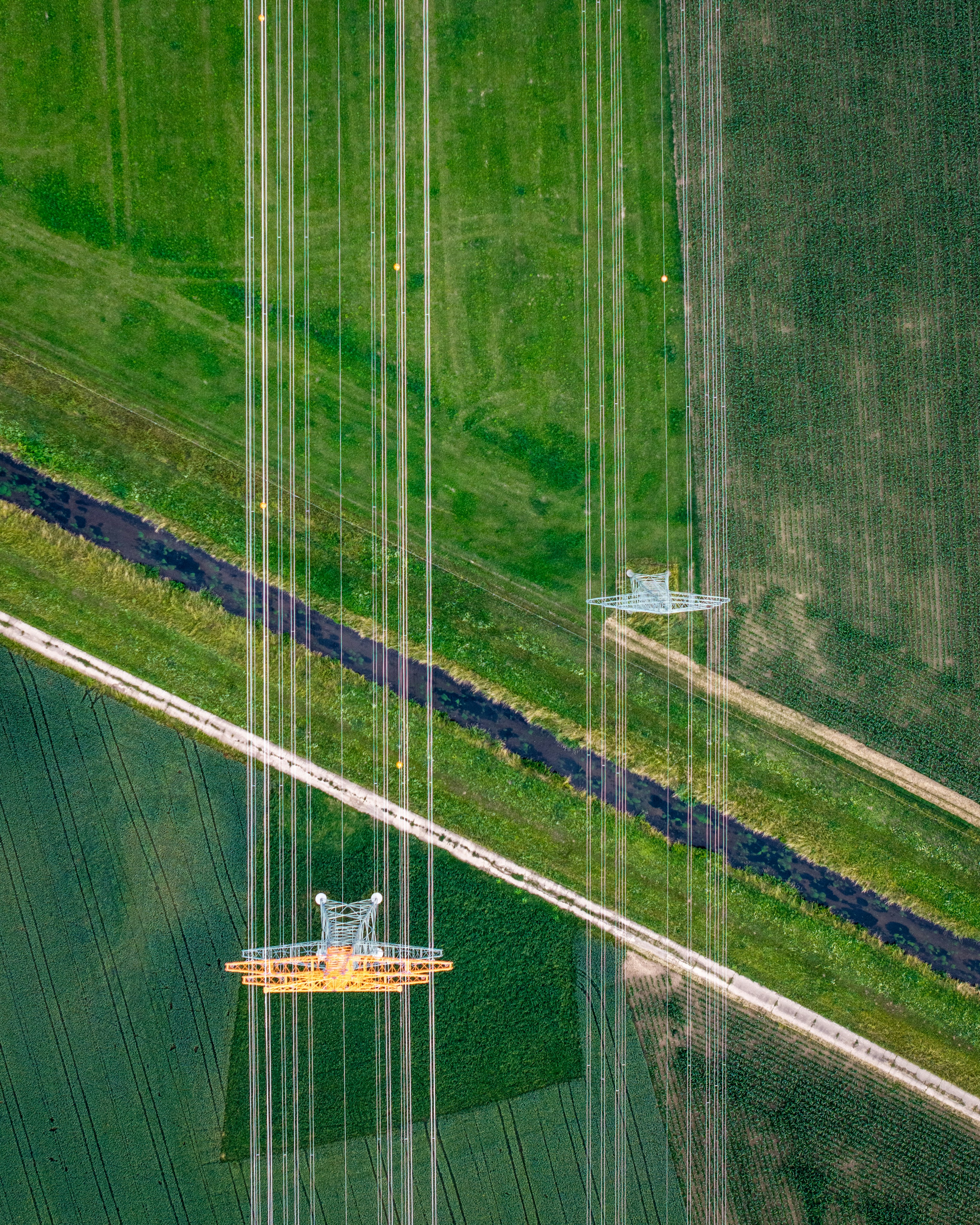 Suspended Grid: Aerial Rails of Light Over Verdant Fields