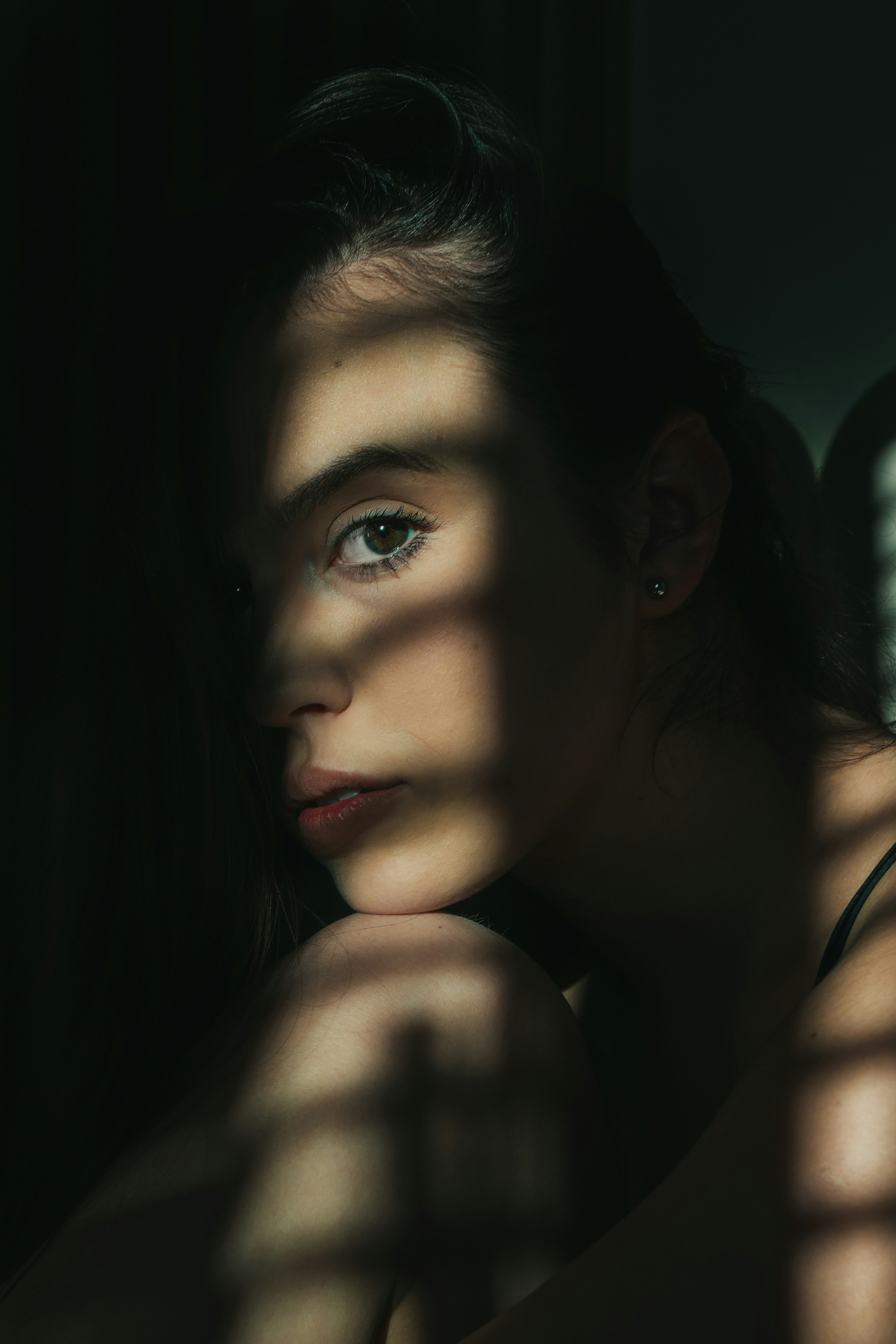 Woman's face partially lit by striped shadows.