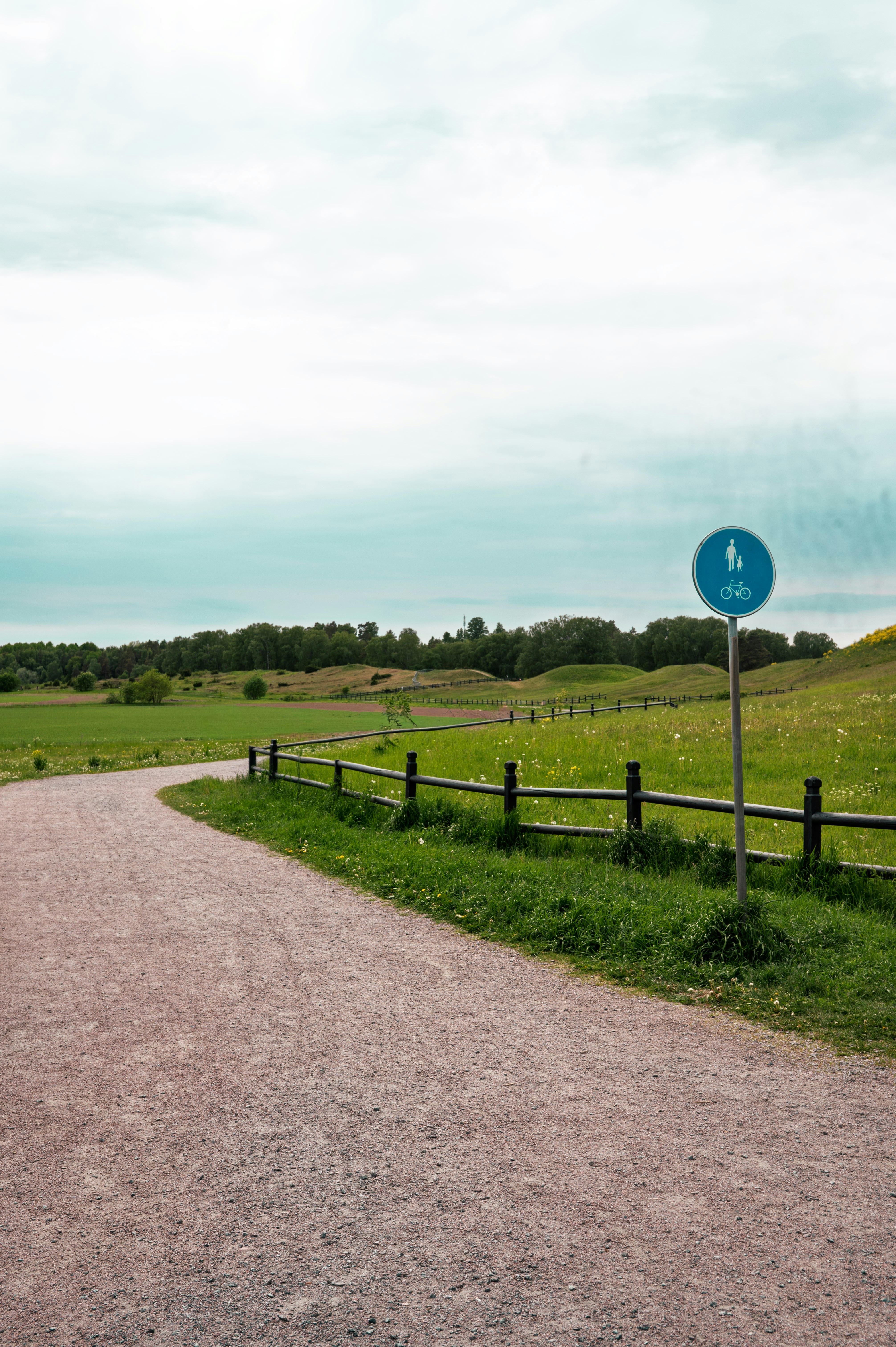 A winding path through green fields with a pedestrian sign.