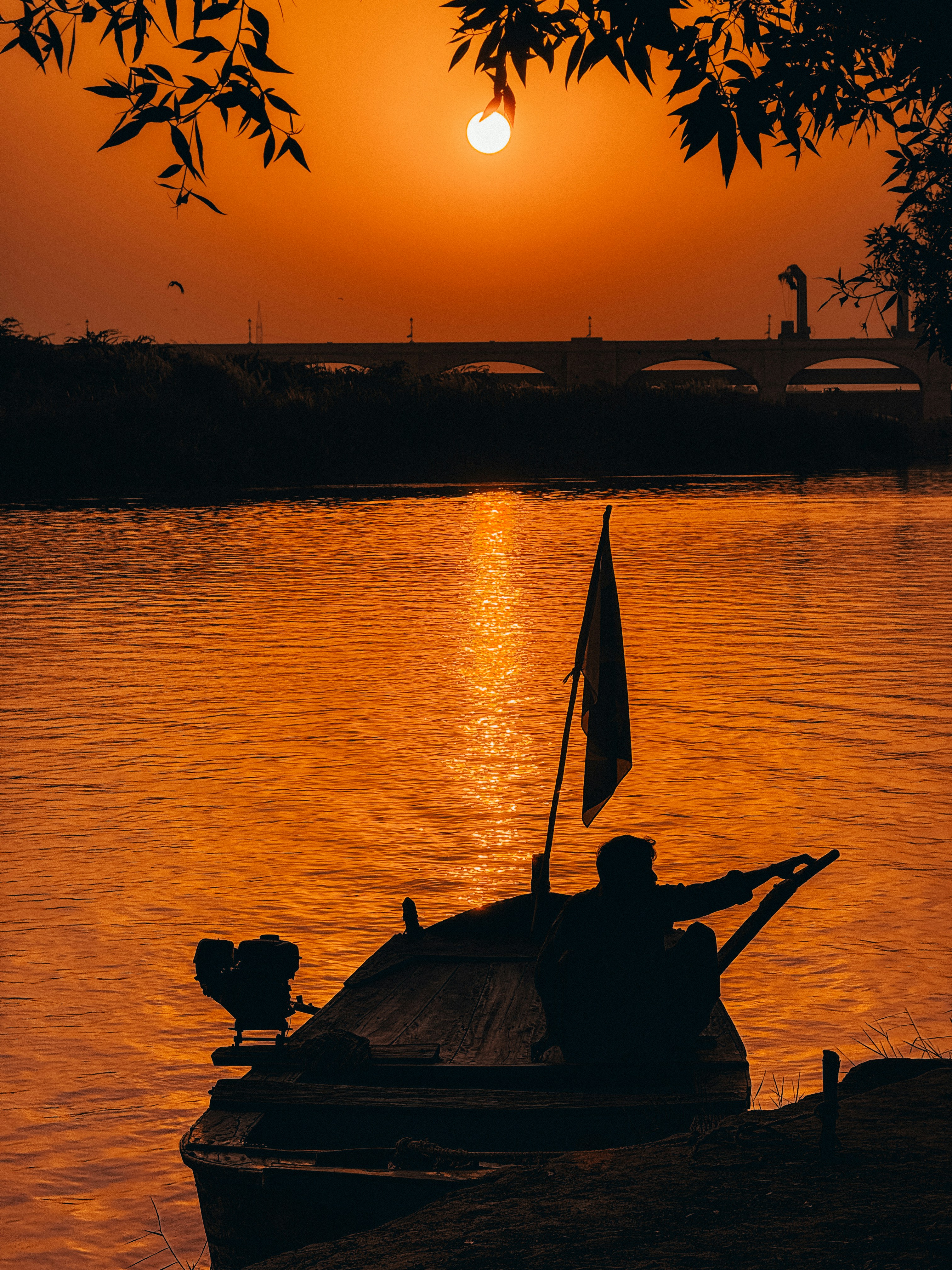 Sunset Over the River: A Silhouetted Boat at Dusk