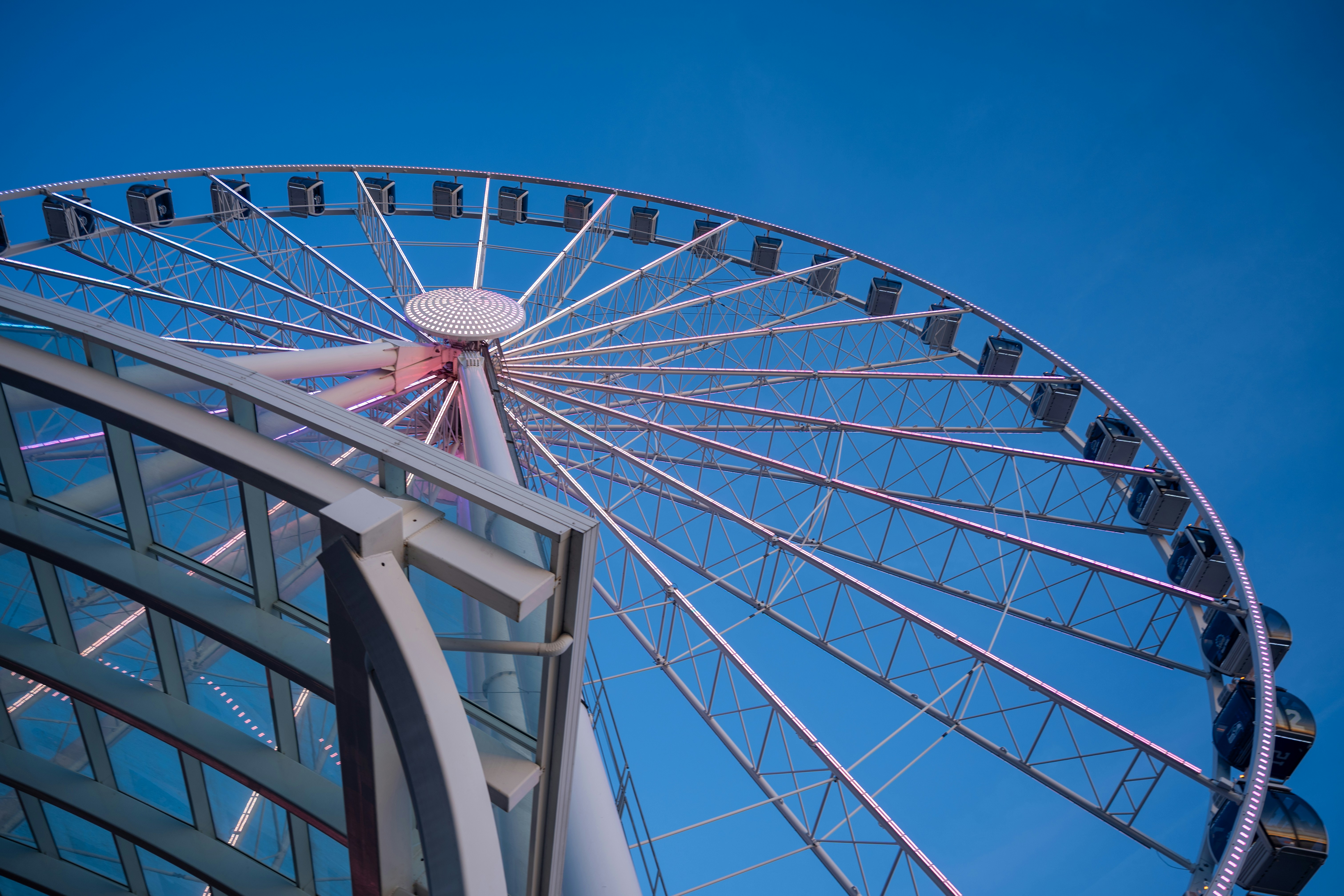 Giant ferris wheel and modern building against a blue sky.