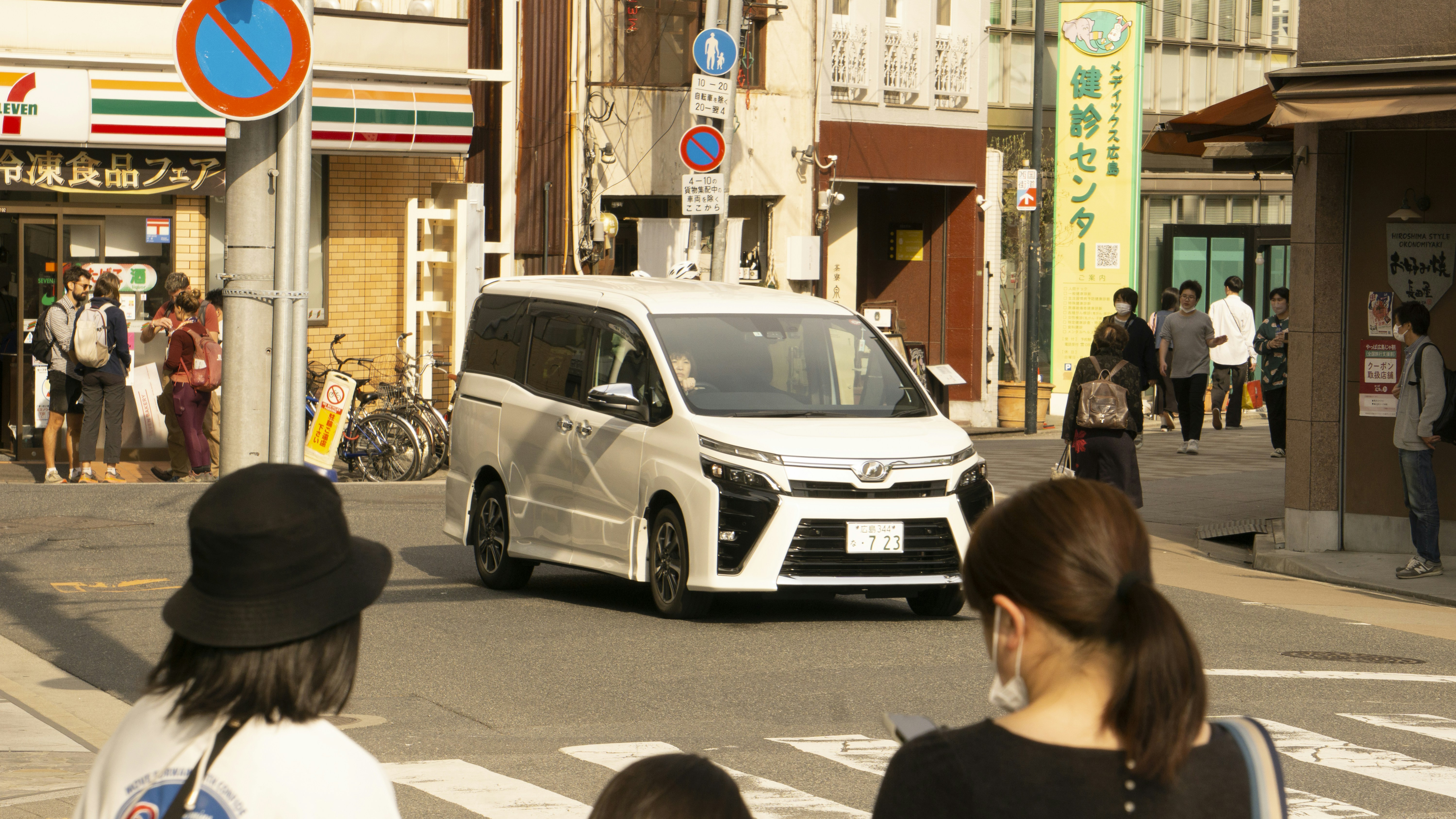 Crosswalk Pulse: A White Minivan Graces a Busy Urban Intersection