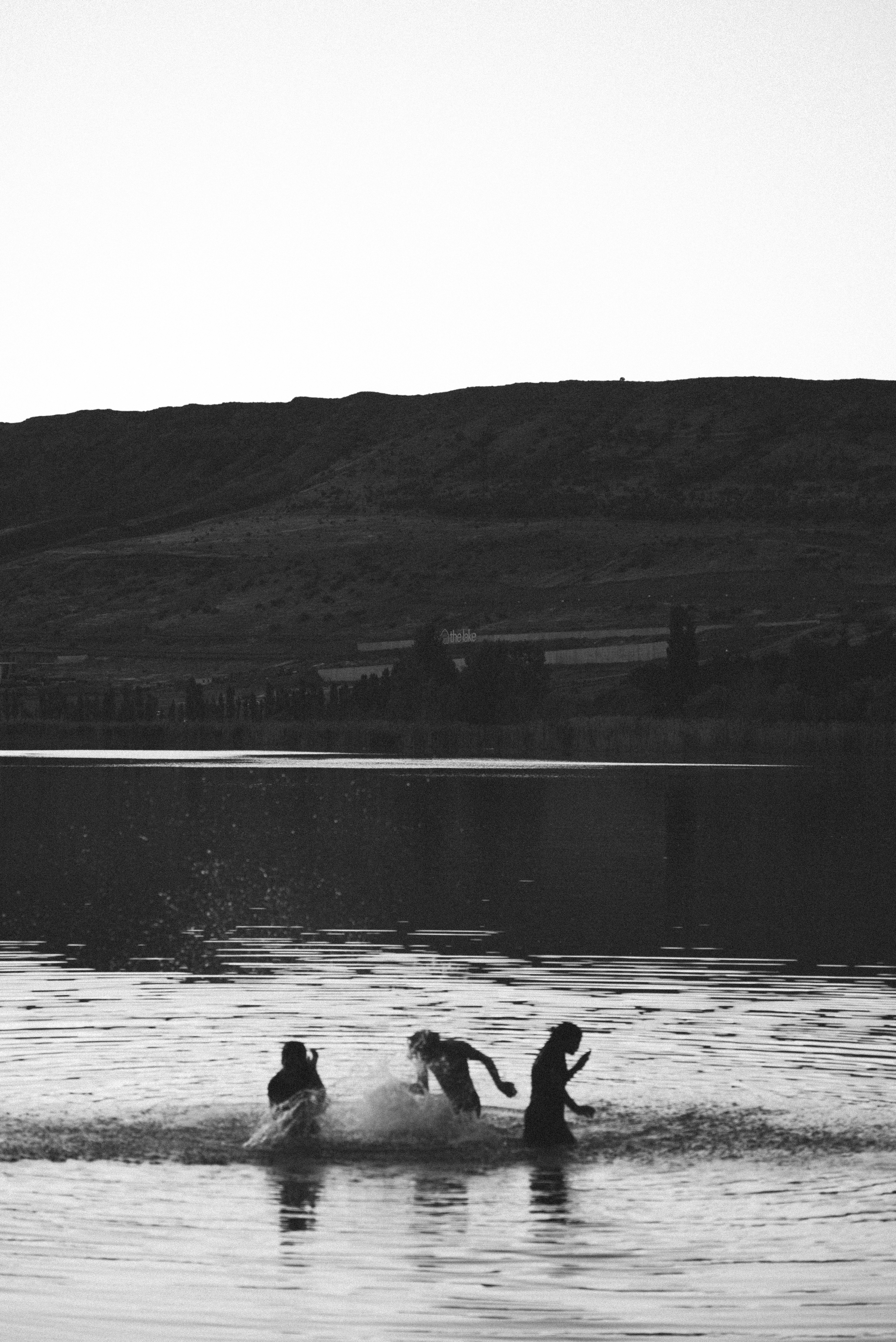 Silhouettes at Dusk: Children Jumping in a Quiet Lake