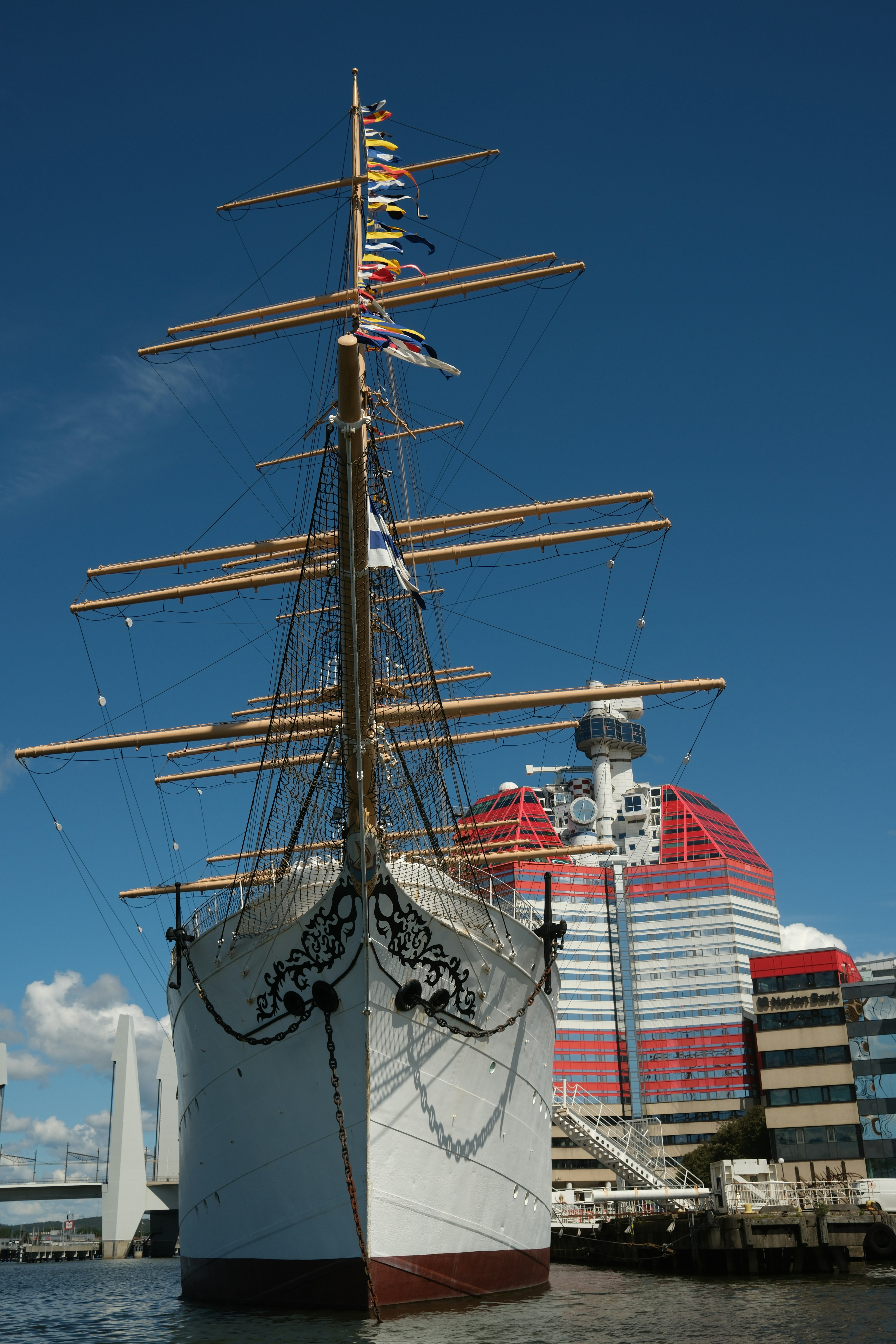 Masted Quiet Power: A Ships' Bow Against a Modern Harbor