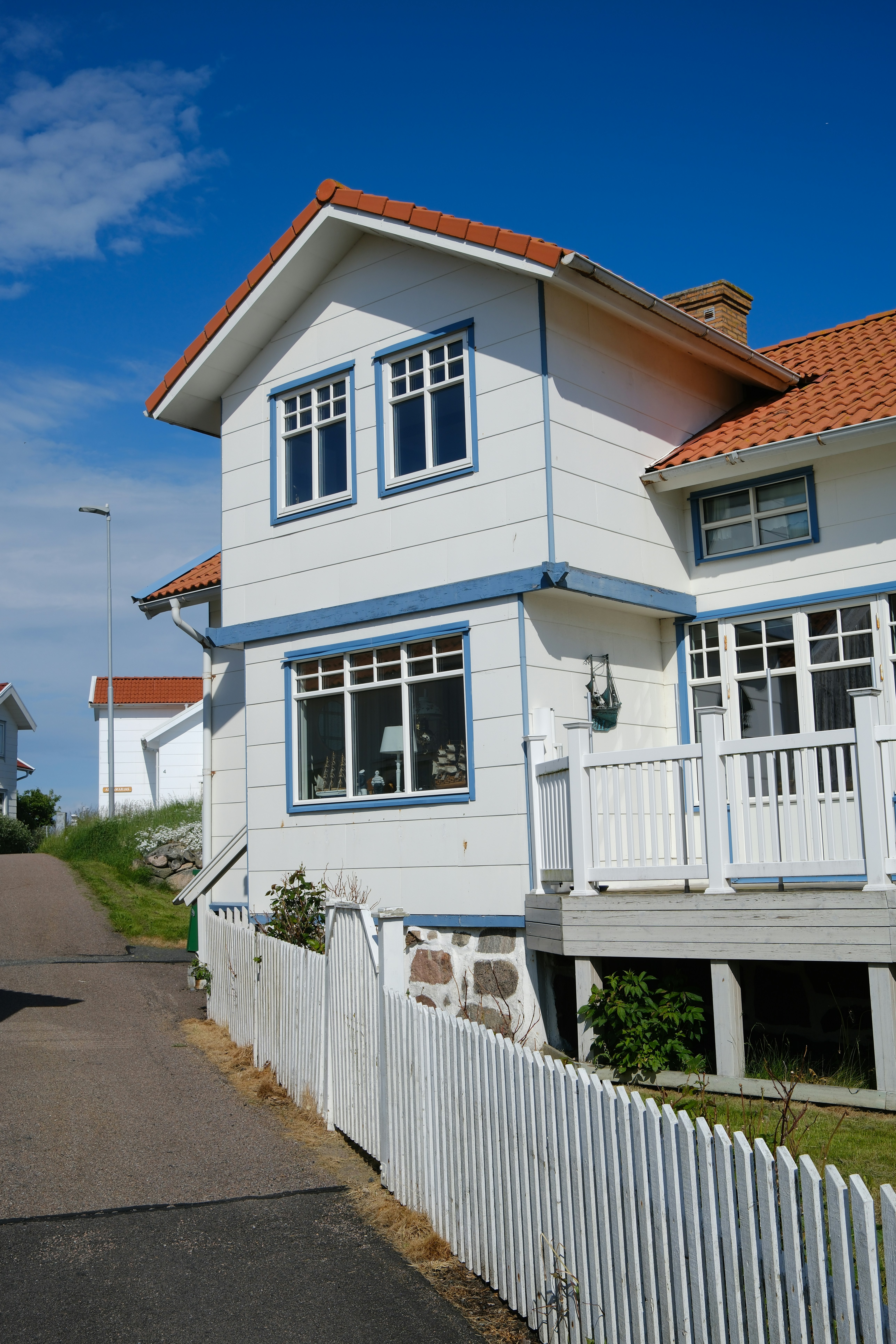 White Coastal House with Blue Trim Under a Clear Blue Sky