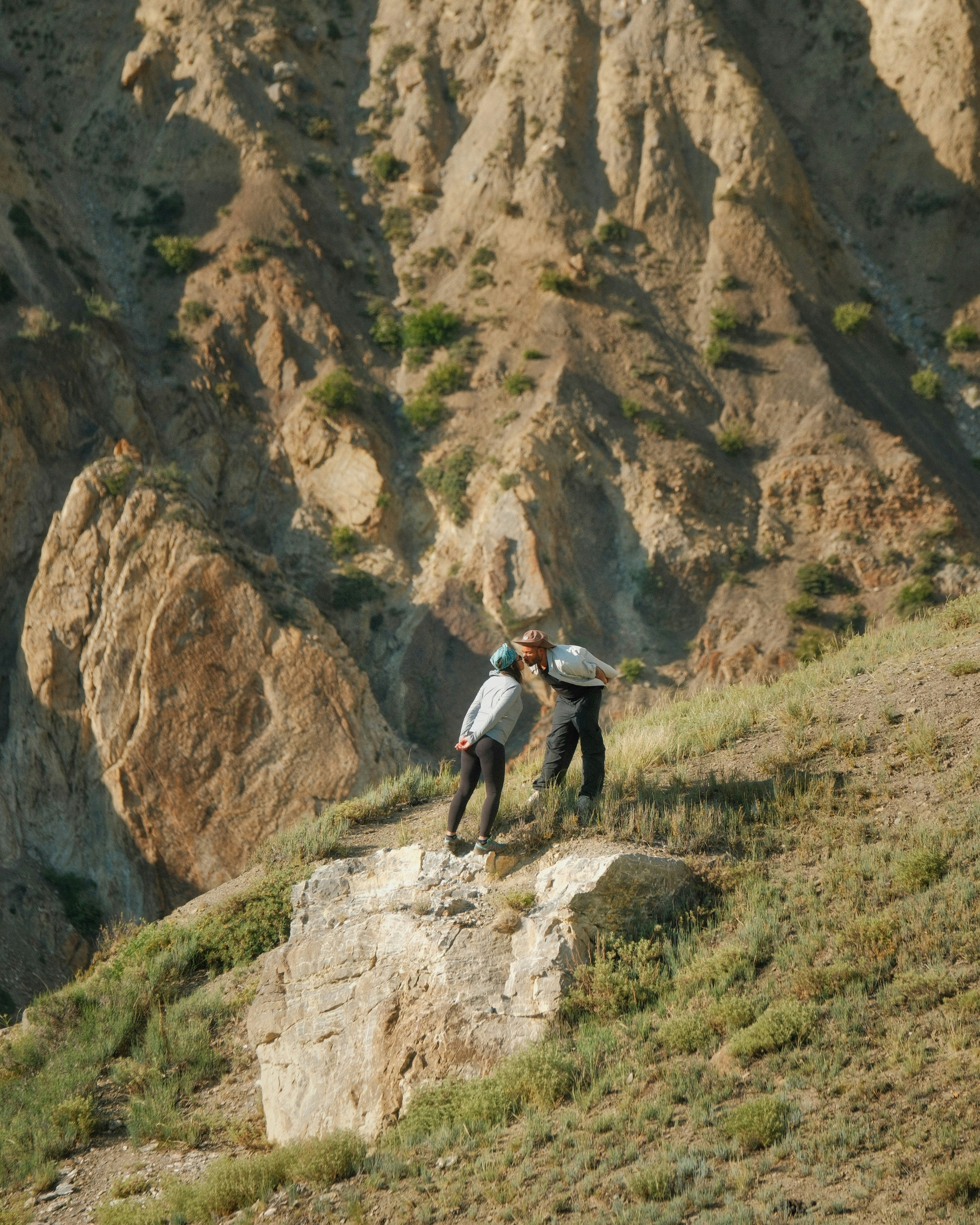 Two hikers on a rocky ledge against rugged canyon walls