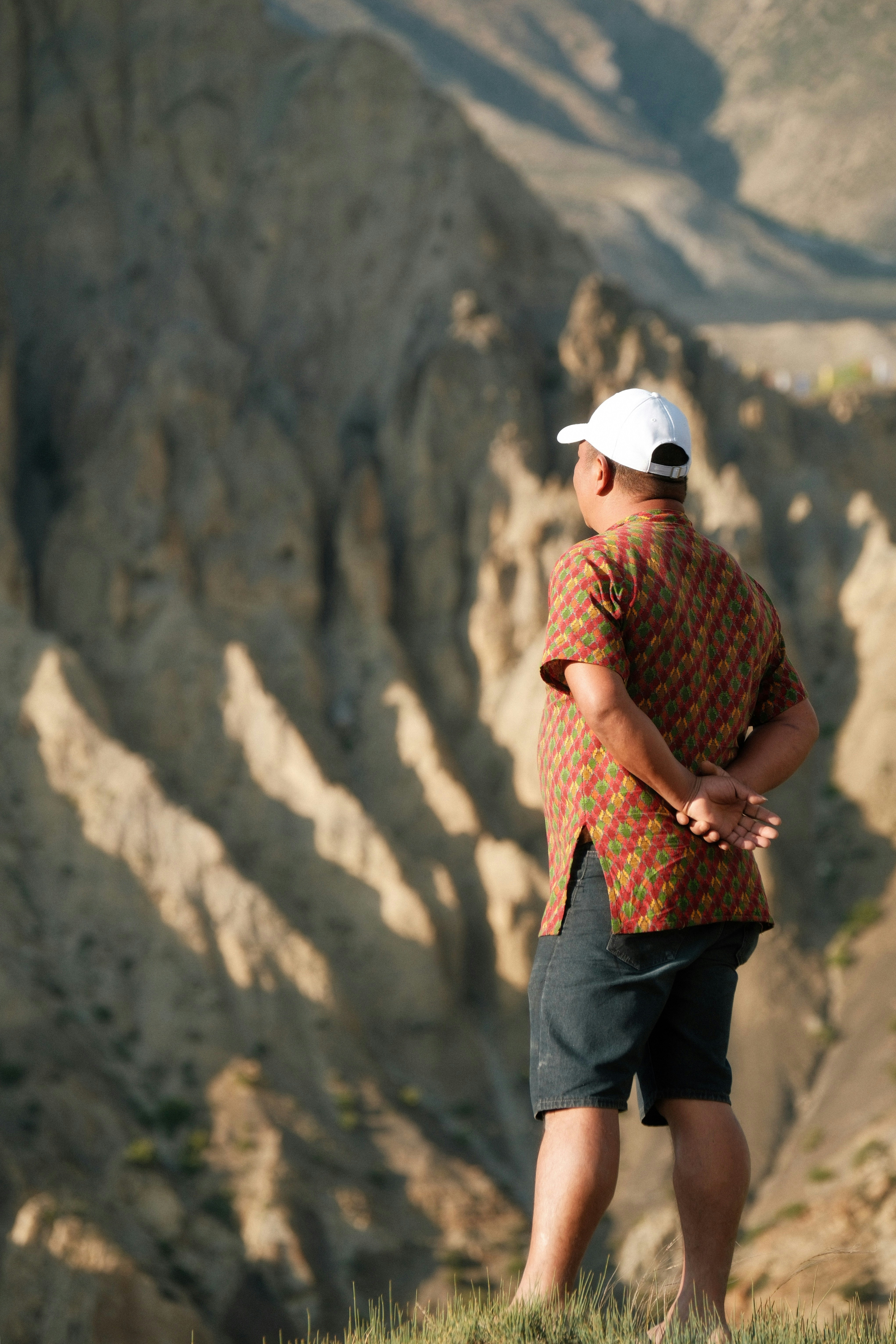 Horizon Watcher: A Man in Patterned Shirt on Cliff Edge
