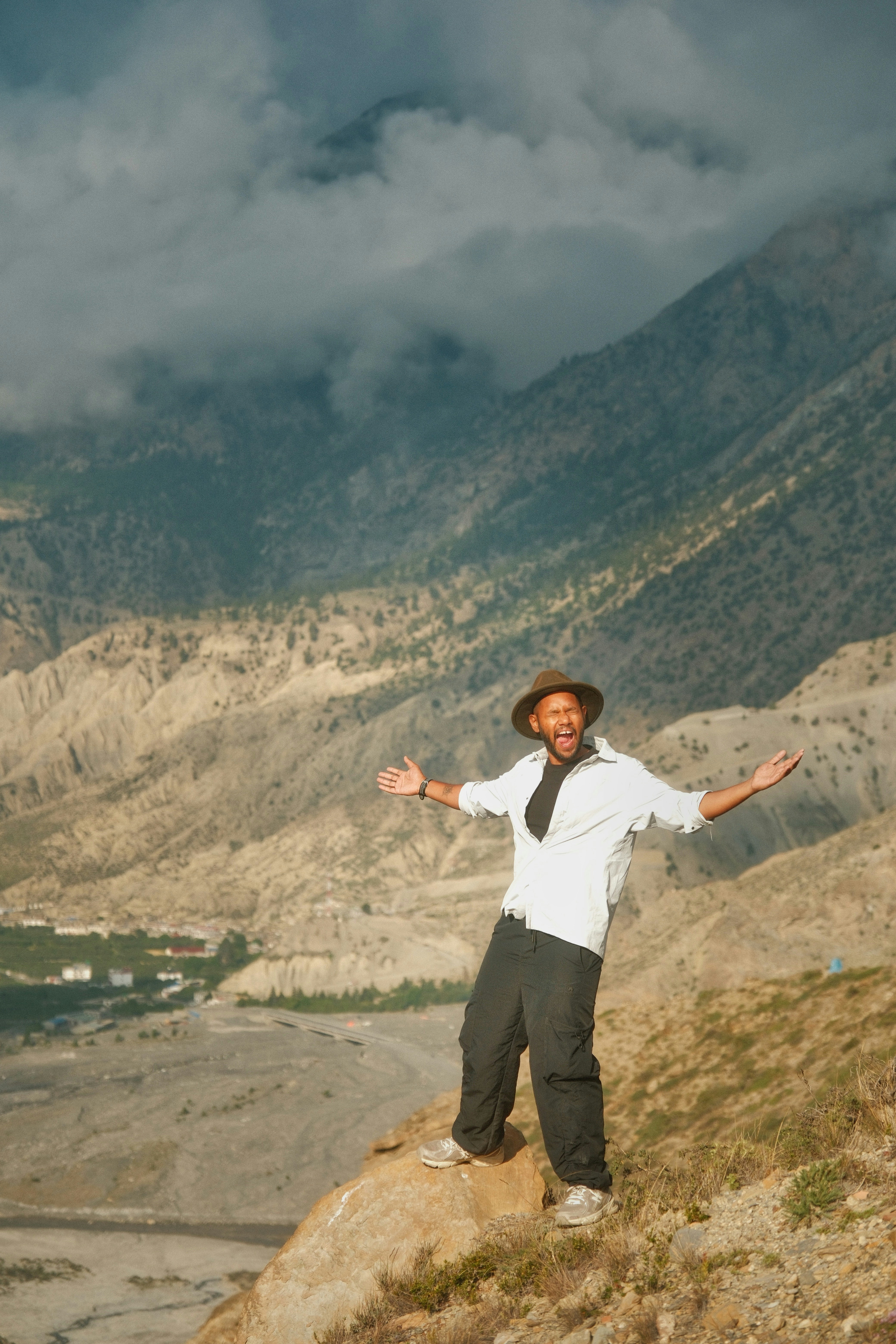 Joy on the Edge: Man Stretches Arms at Mountain Vista