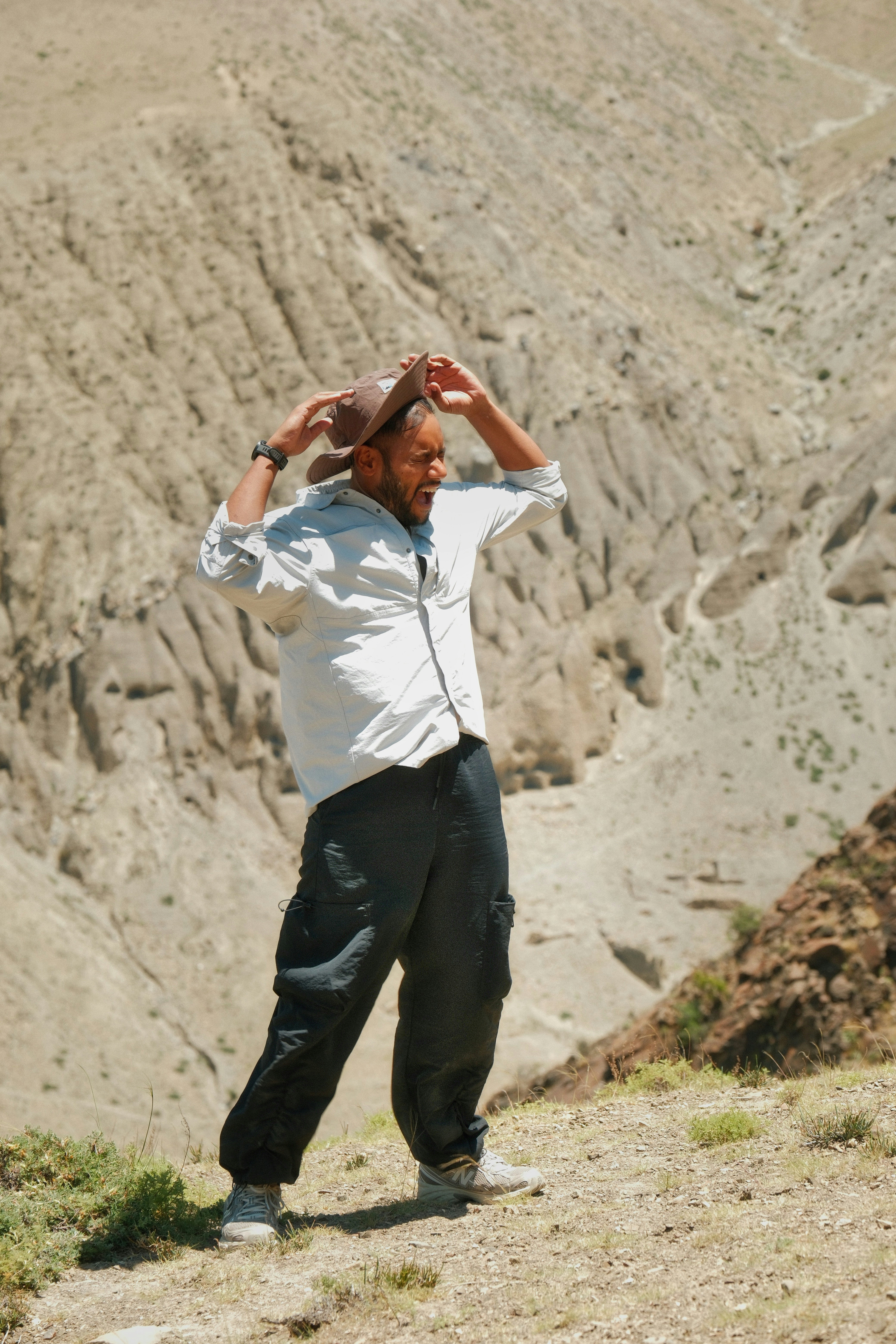 Hiker in a Sunlit Gully Reaches for the Hat