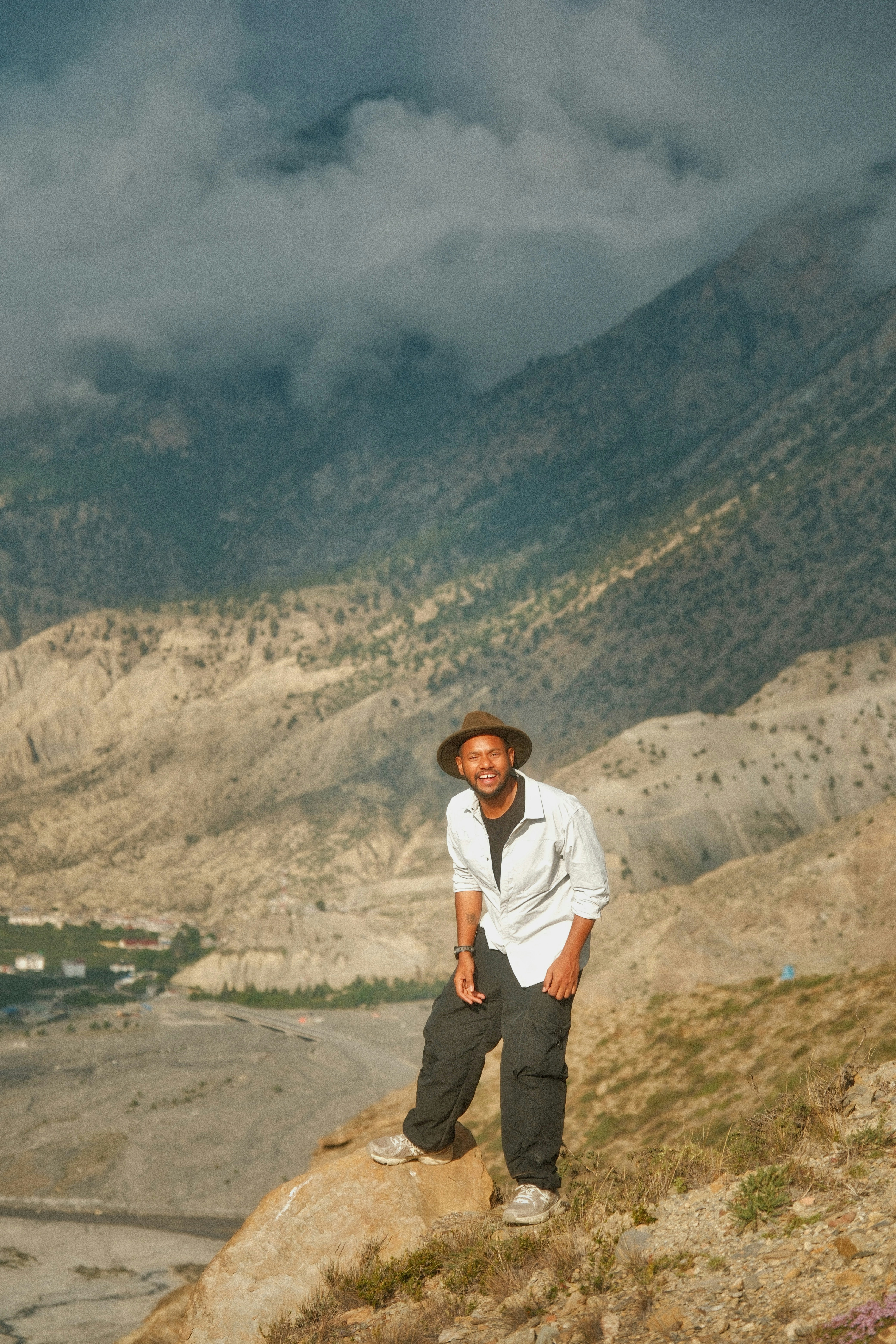 Hiker at the Edge: A Man in a White Shirt and Hat on a Mountain Ridge
