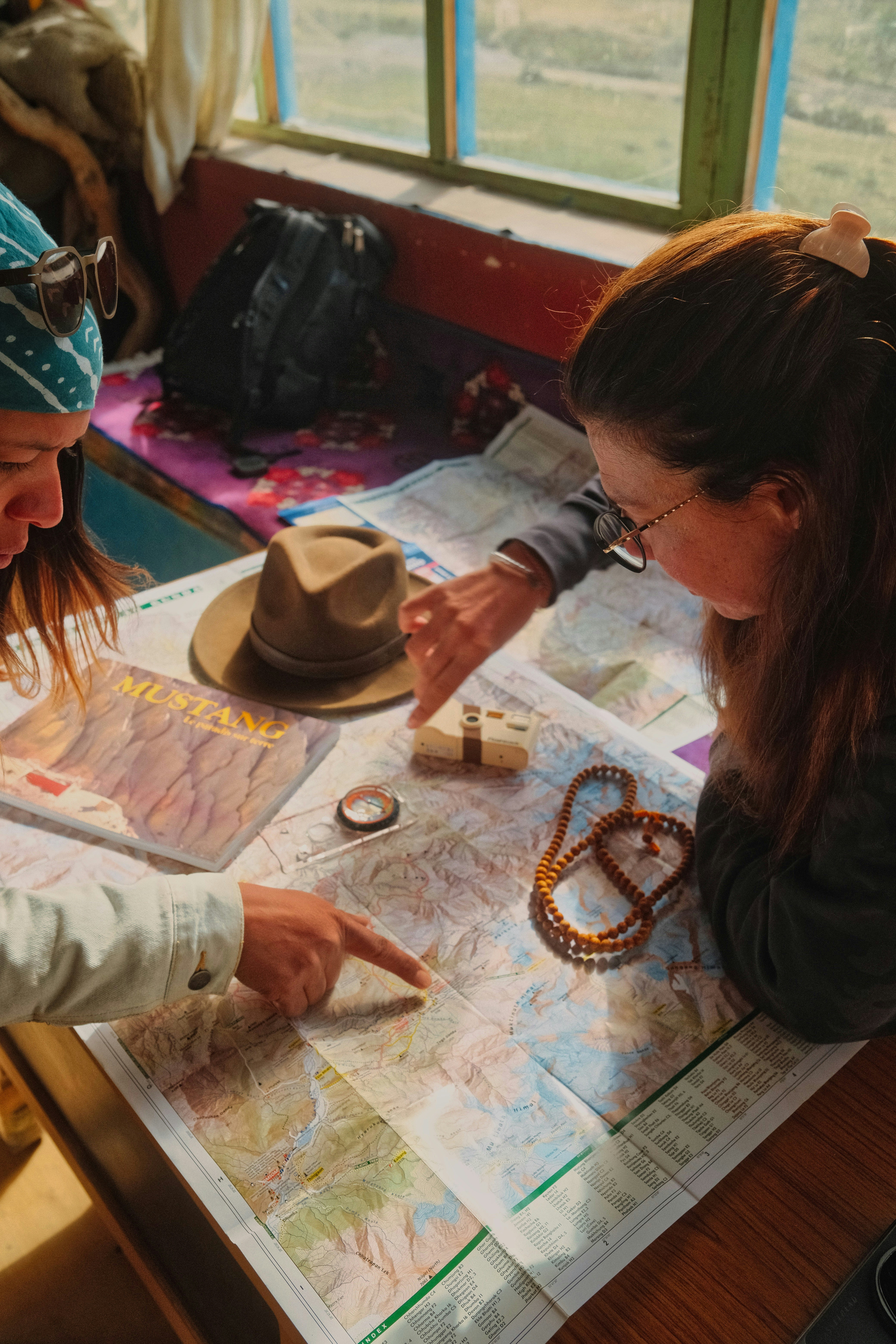 Two Adventurers Decode a Mountain Map at a Cozy Window Table