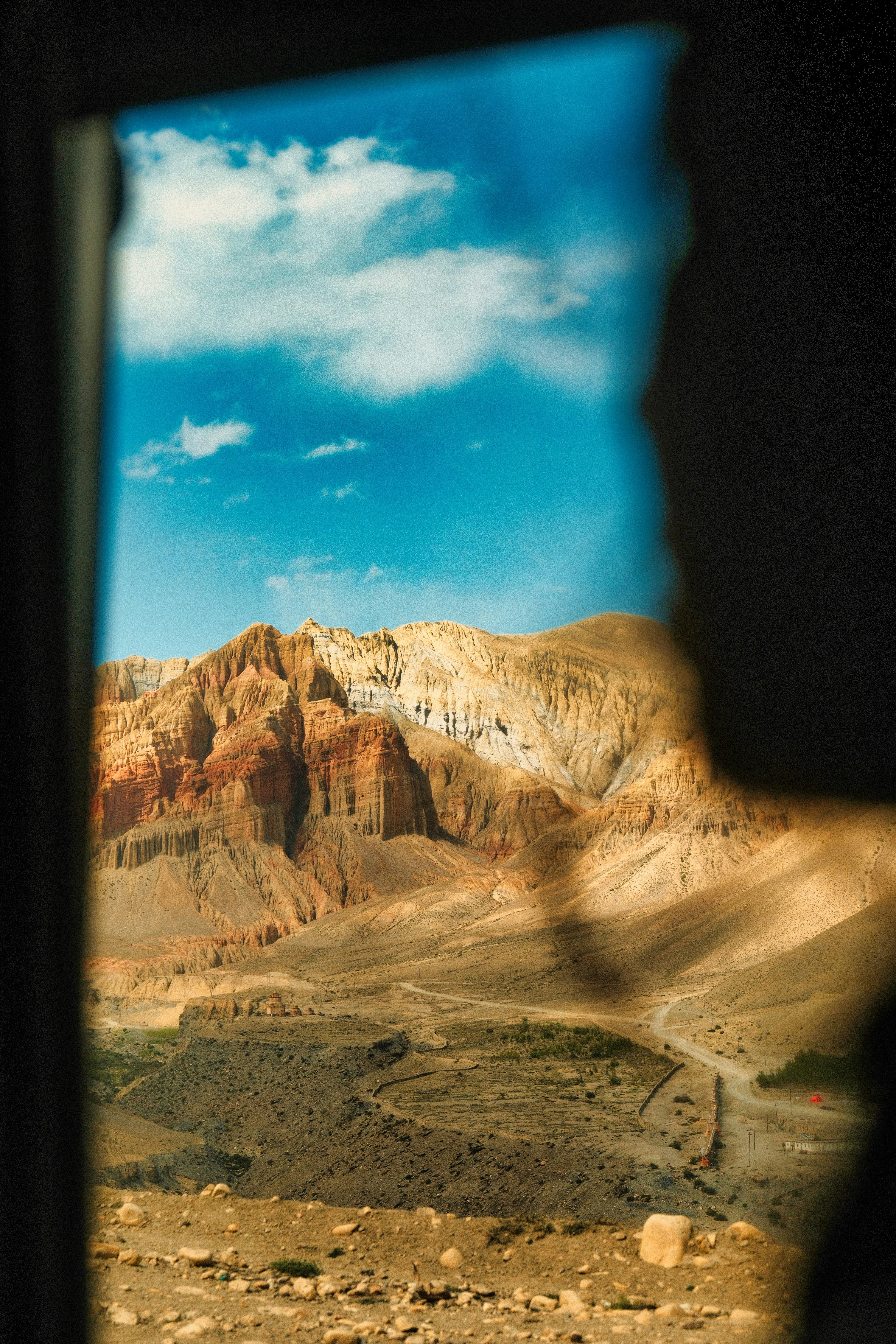 Framed view of colorful arid mountains under a blue sky.